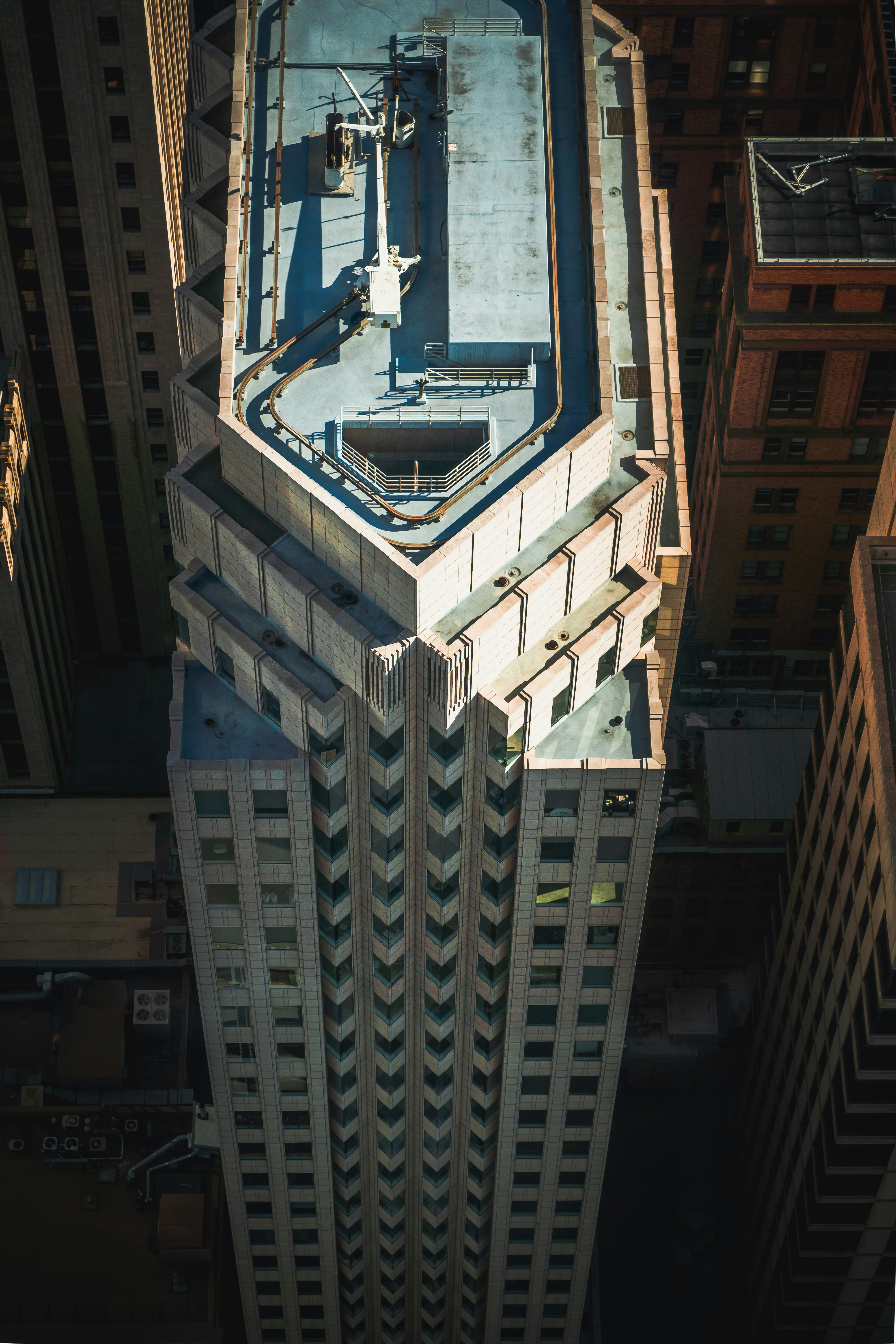 Blue Rooftop Apex: Aerial Perspective of a Sharp-Cornered Skyscraper