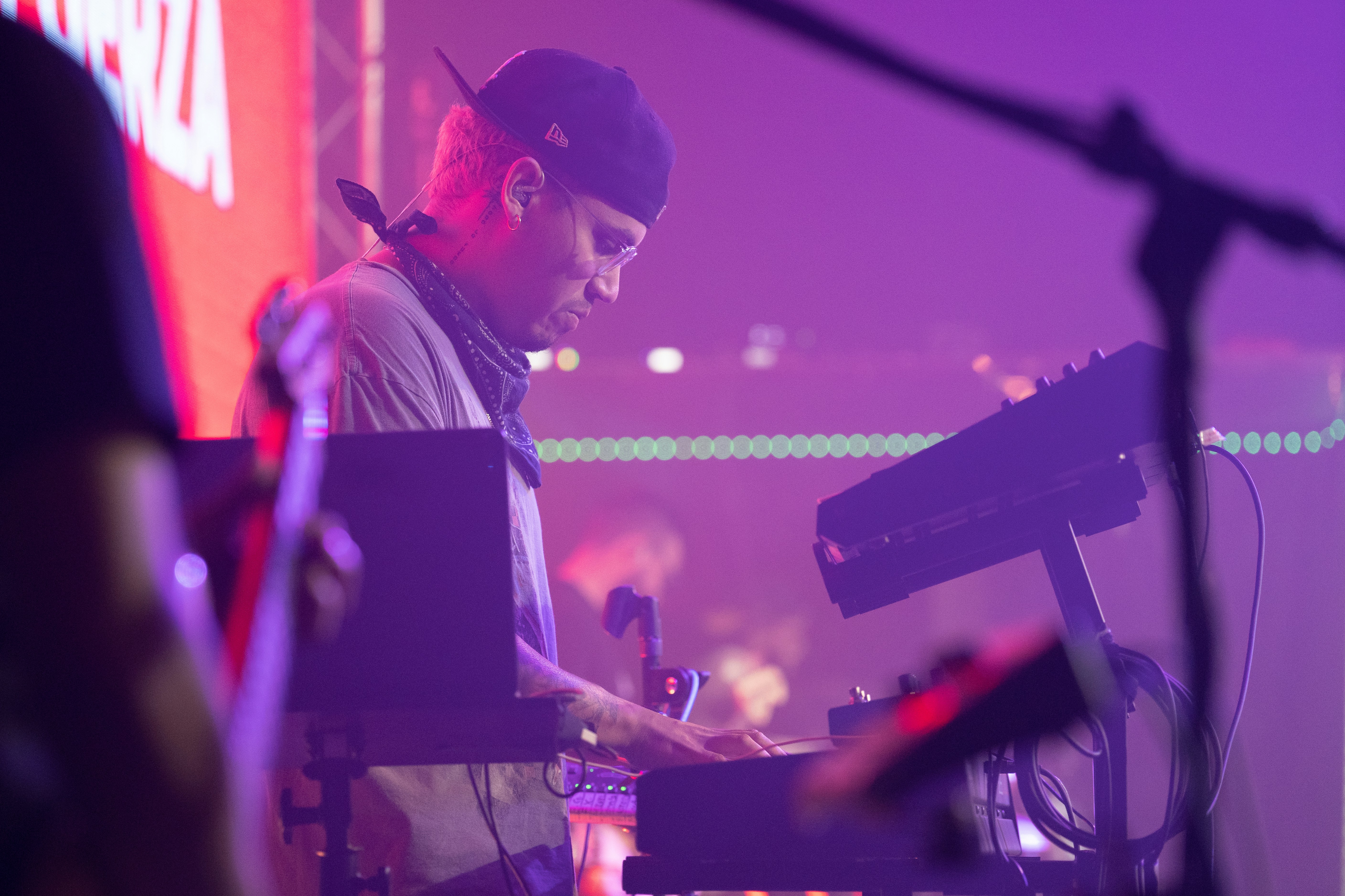 Musician engaged in a live electronic performance, surrounded by vibrant stage lighting and instruments. The atmosphere conveys energy and creativity.