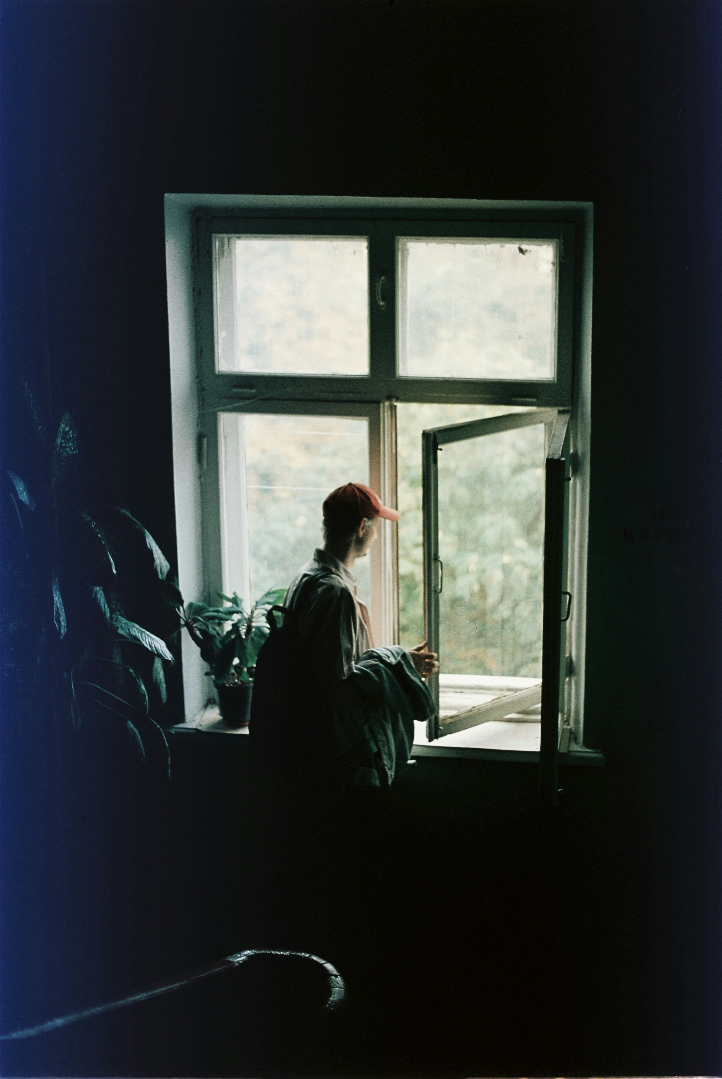 A person sitting on a window sill looking out the window photo – Free ...