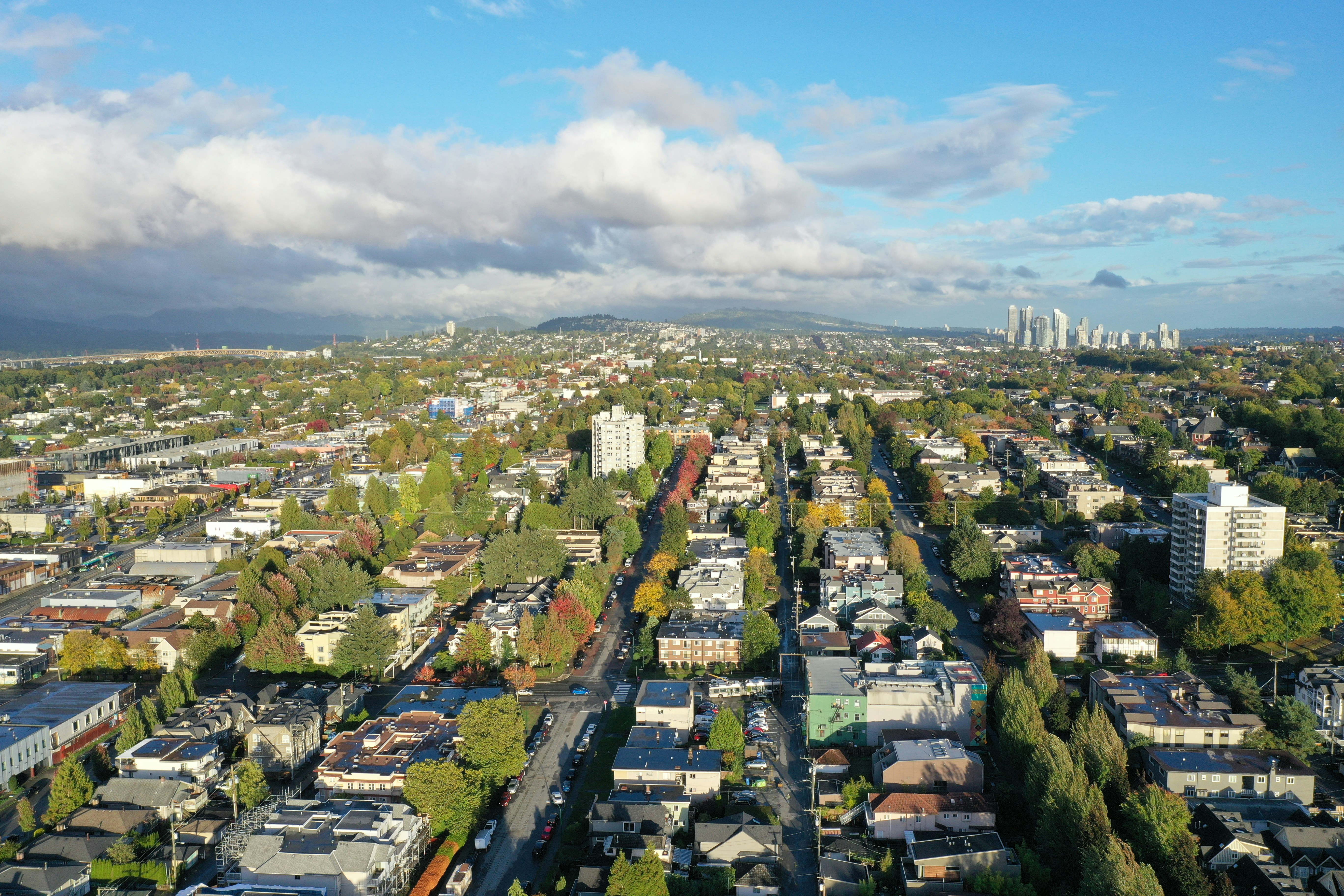 Aerial view showcasing a vibrant urban landscape with diverse architecture and tree-lined streets under a dynamic sky.