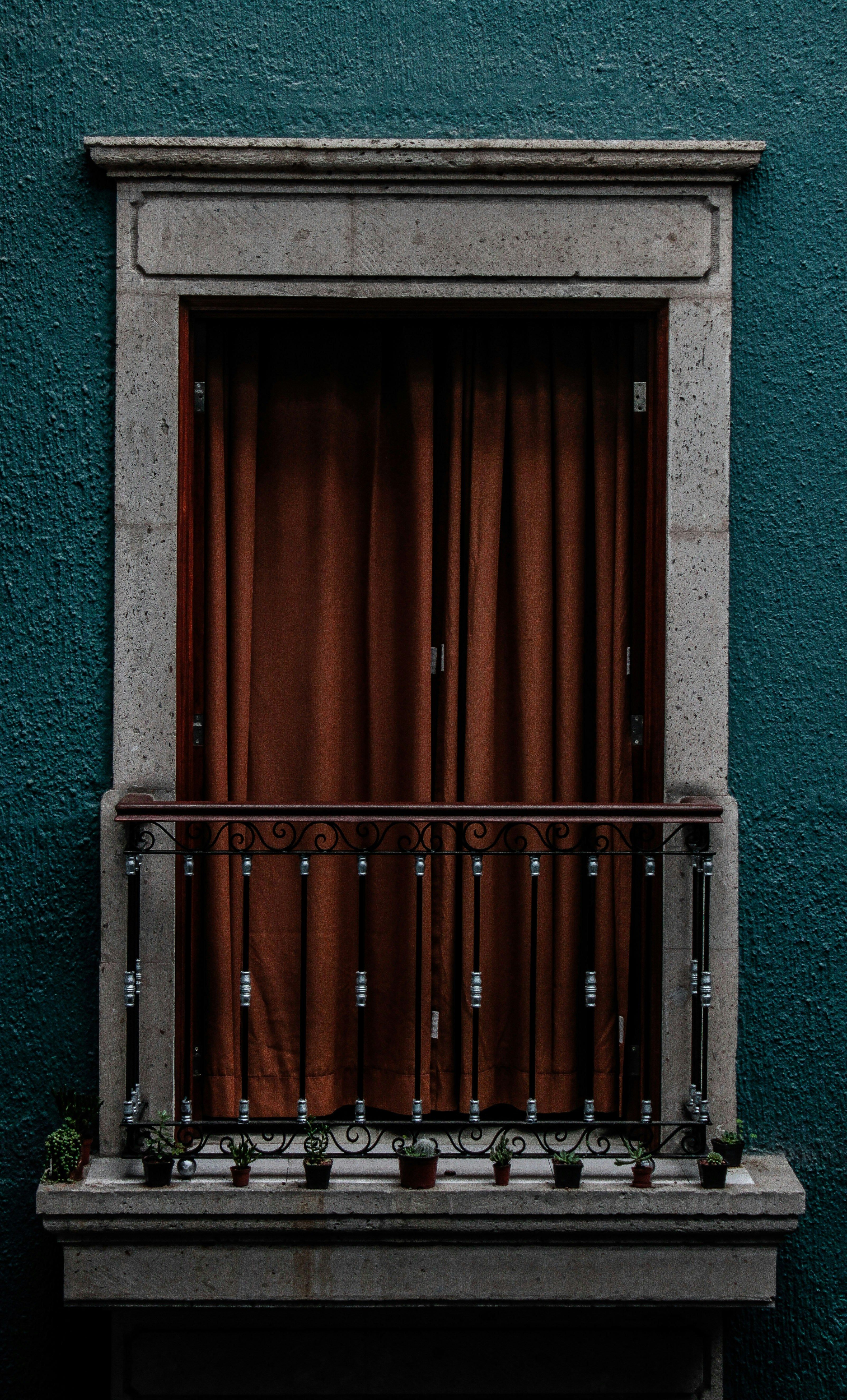 Teal Facade Frame: Rust Curtain Behind Wrought-Iron Balcony