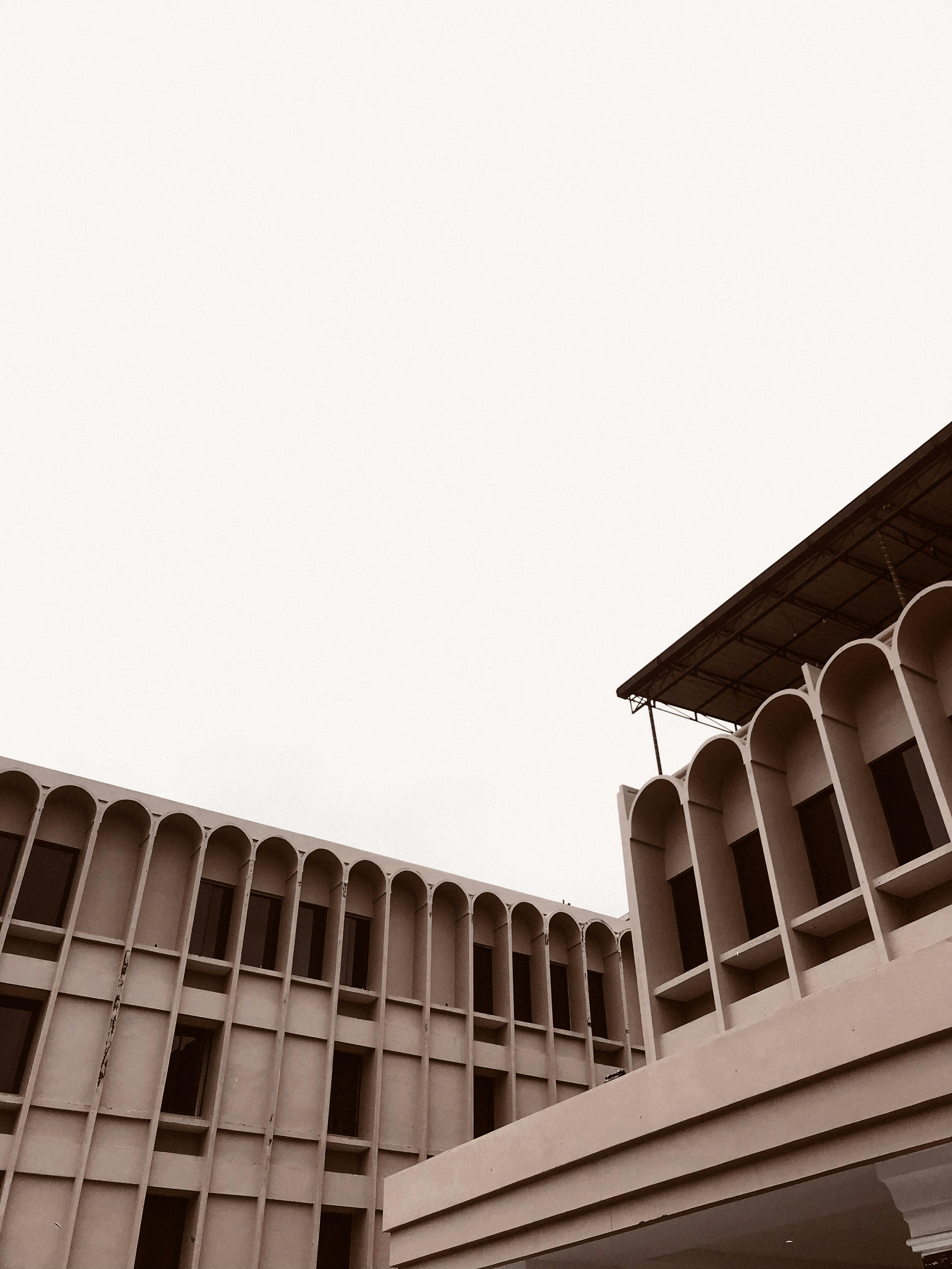 Symmetrical building with arched windows and minimalistic design under an overcast sky.