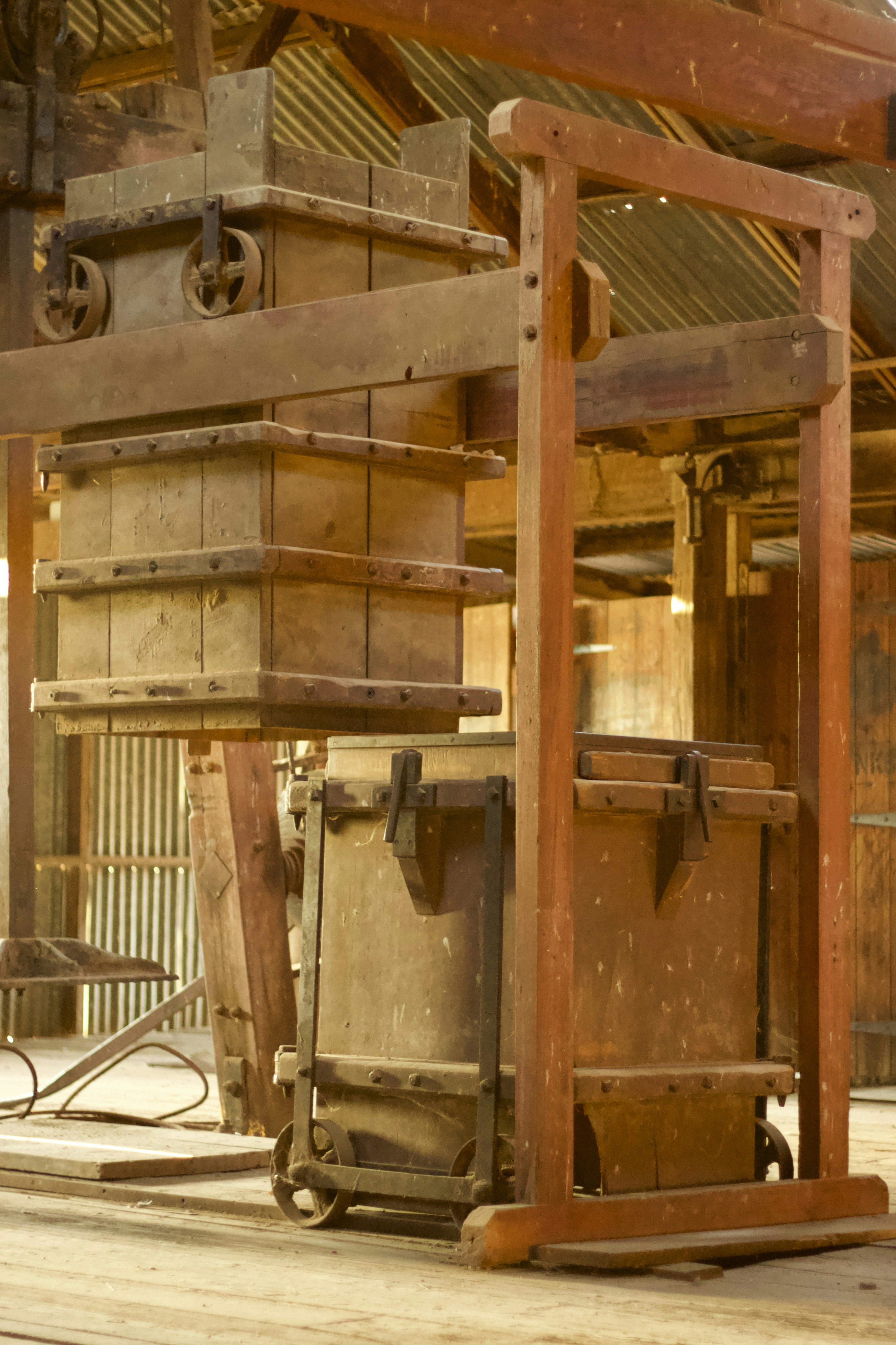 Rustic wooden press with metal components, showcasing the craftsmanship of a bygone era in an old barn setting.