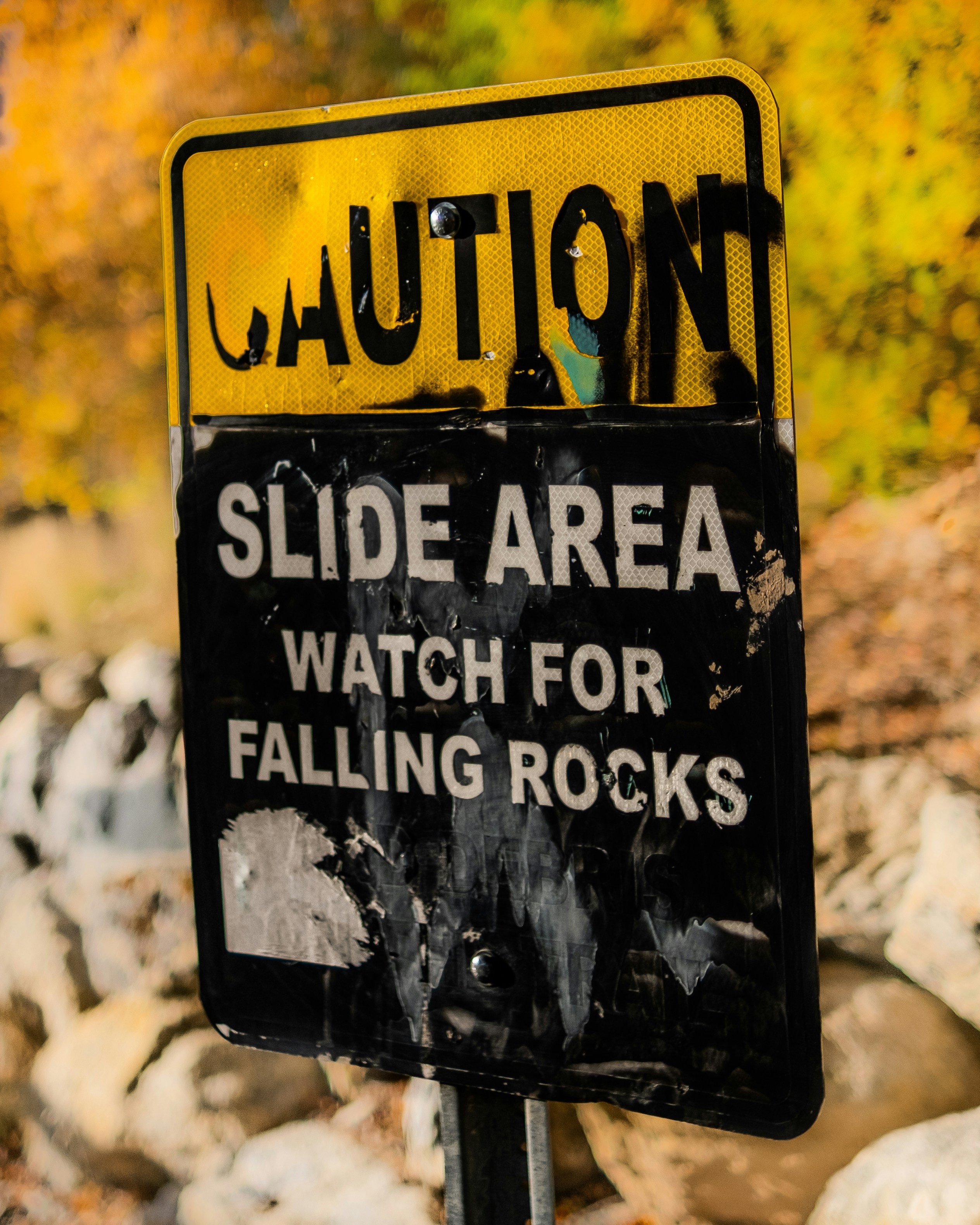 A black and yellow sign that says caution slide area watch for falling ...