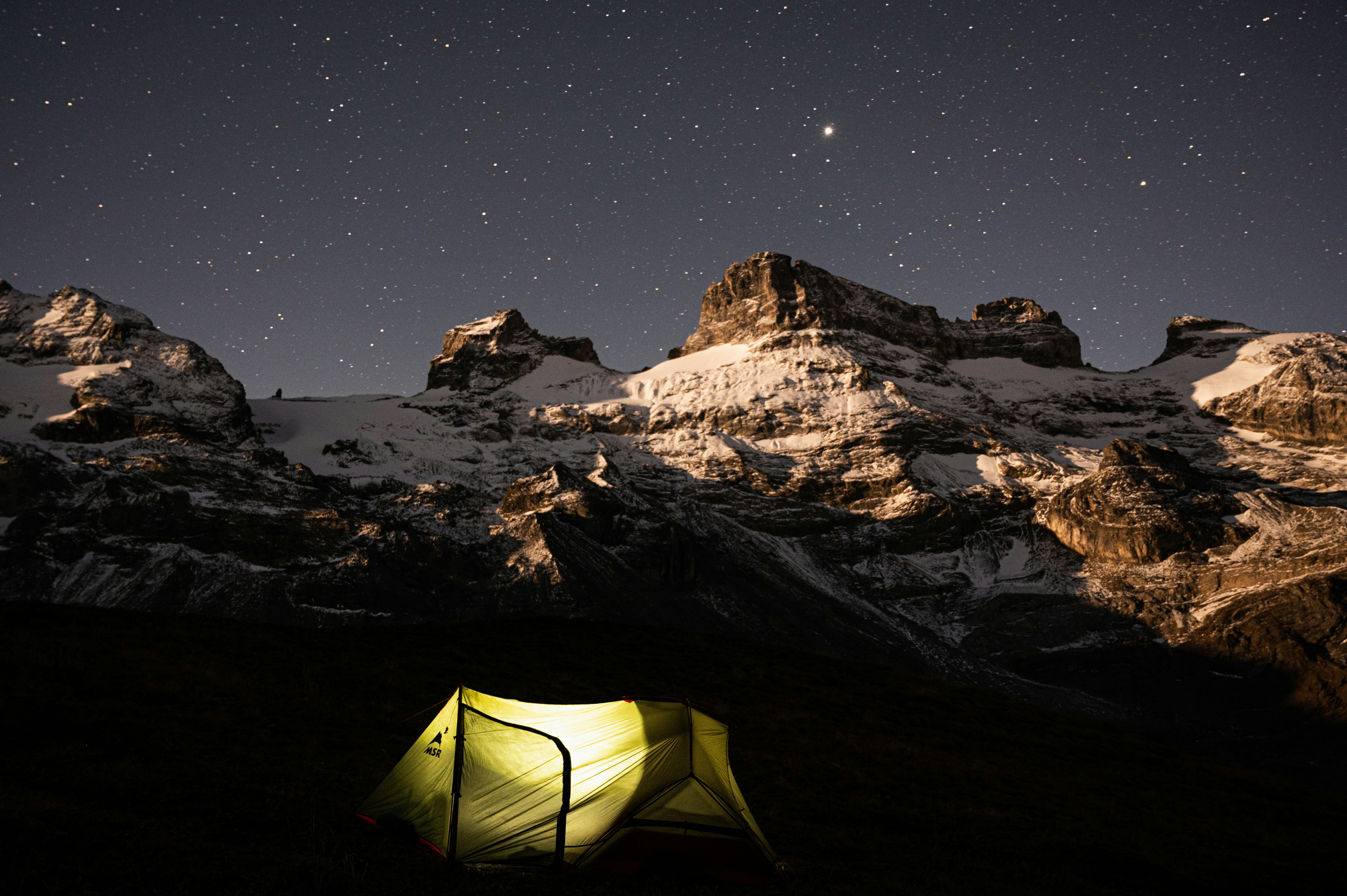 a tent pitched up in the mountains at night