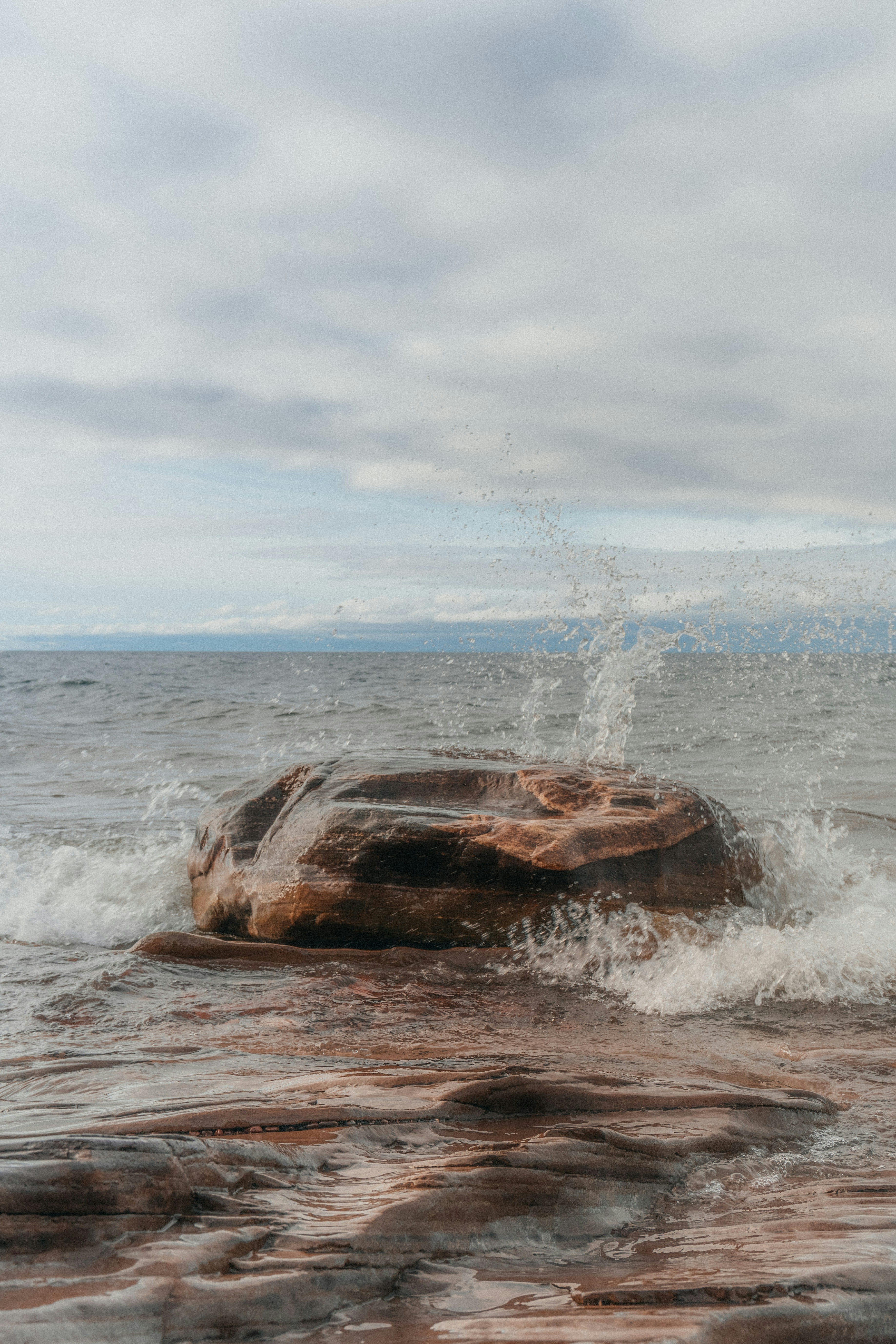 Sea-Sculpted Rock Crowned by Spray Under a Cloudy Horizon