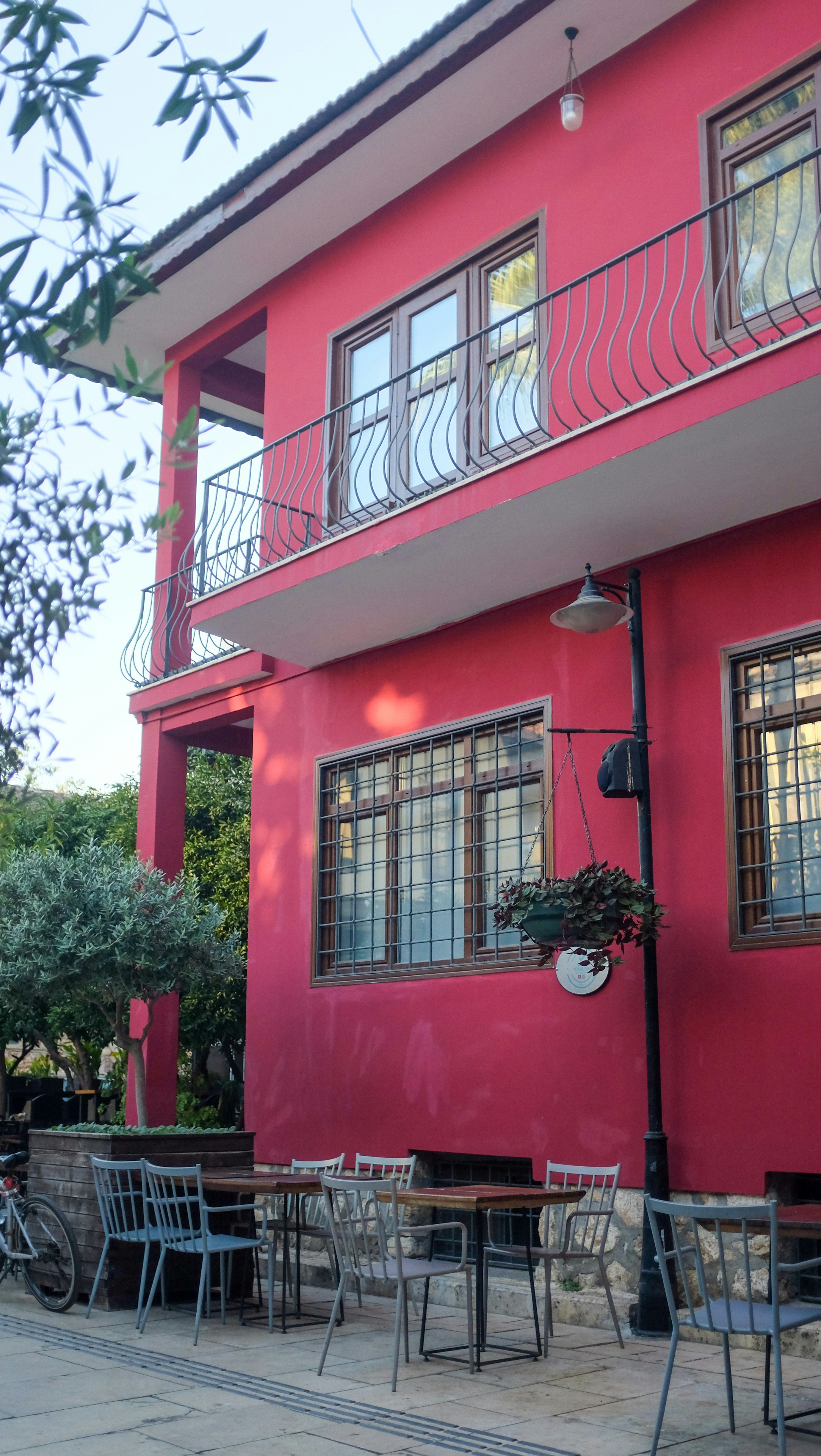 Crimson Facade with Wrought-Iron Balcony and a Quiet Café Corner