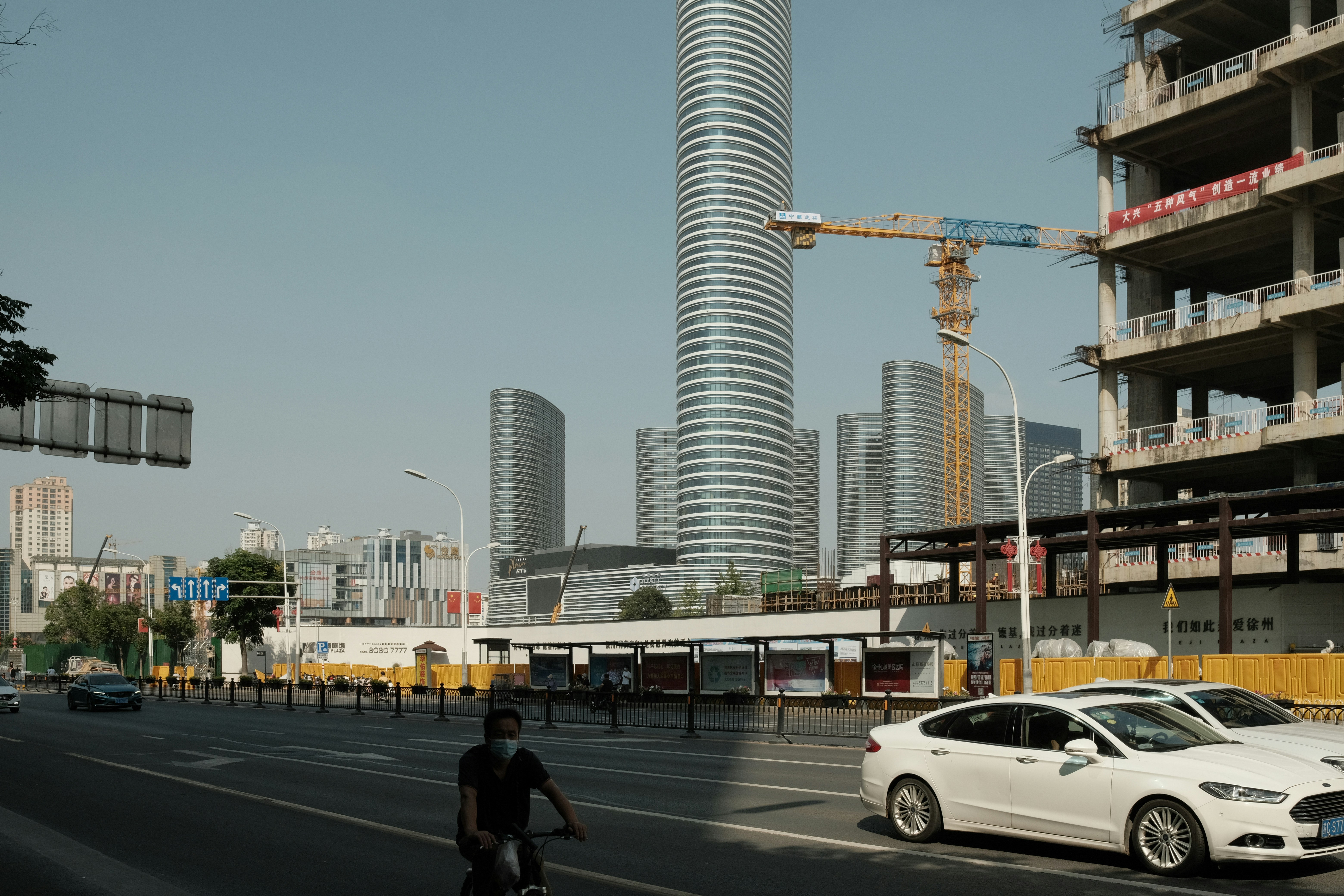 A white car driving down a street next to tall buildings photo – Free ...