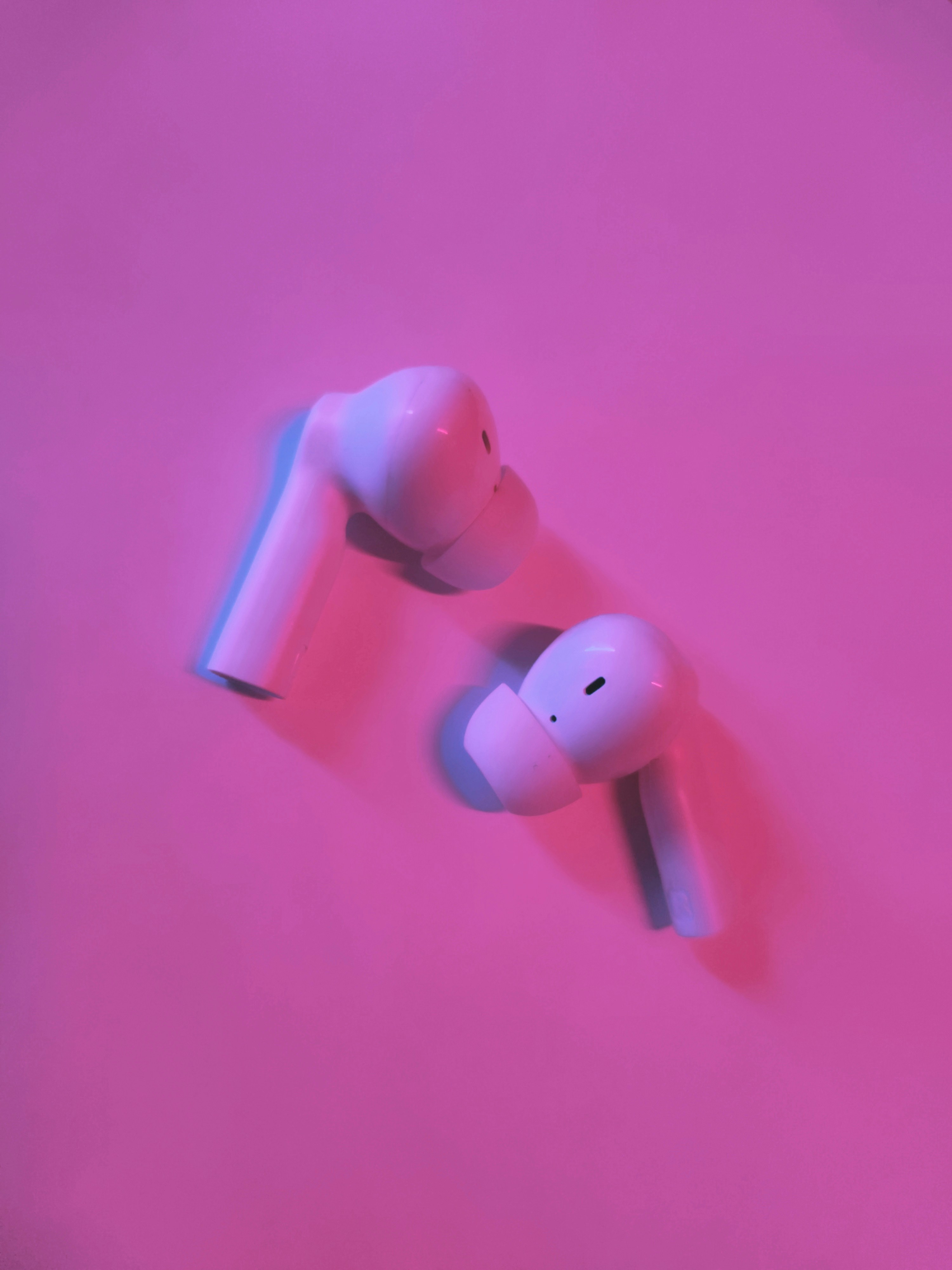 A pair of ear buds sitting on top of a pink surface photo – Free Amoled ...