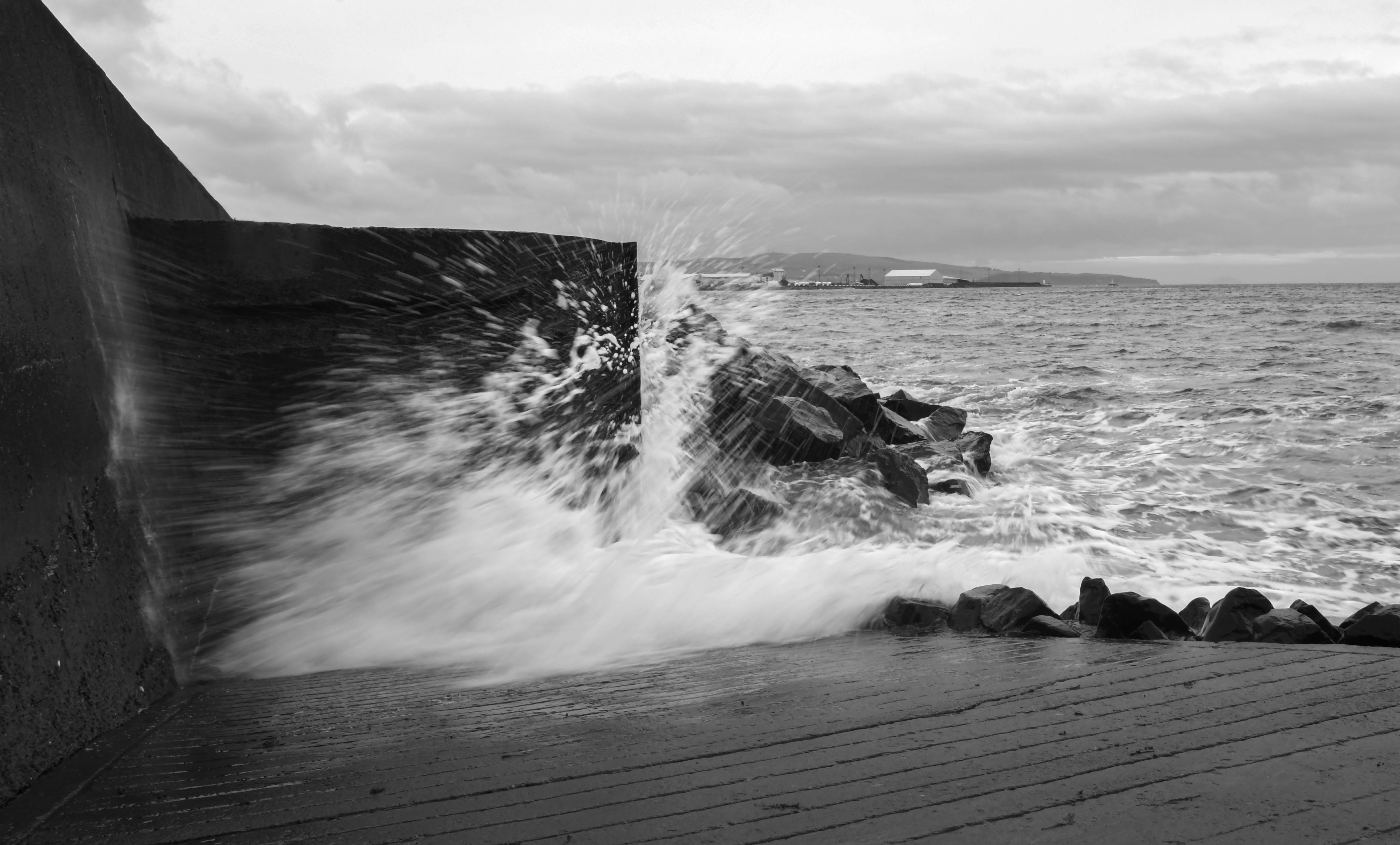 Une photo en noir et blanc d’une vague s’écrasant contre un mur photo ...