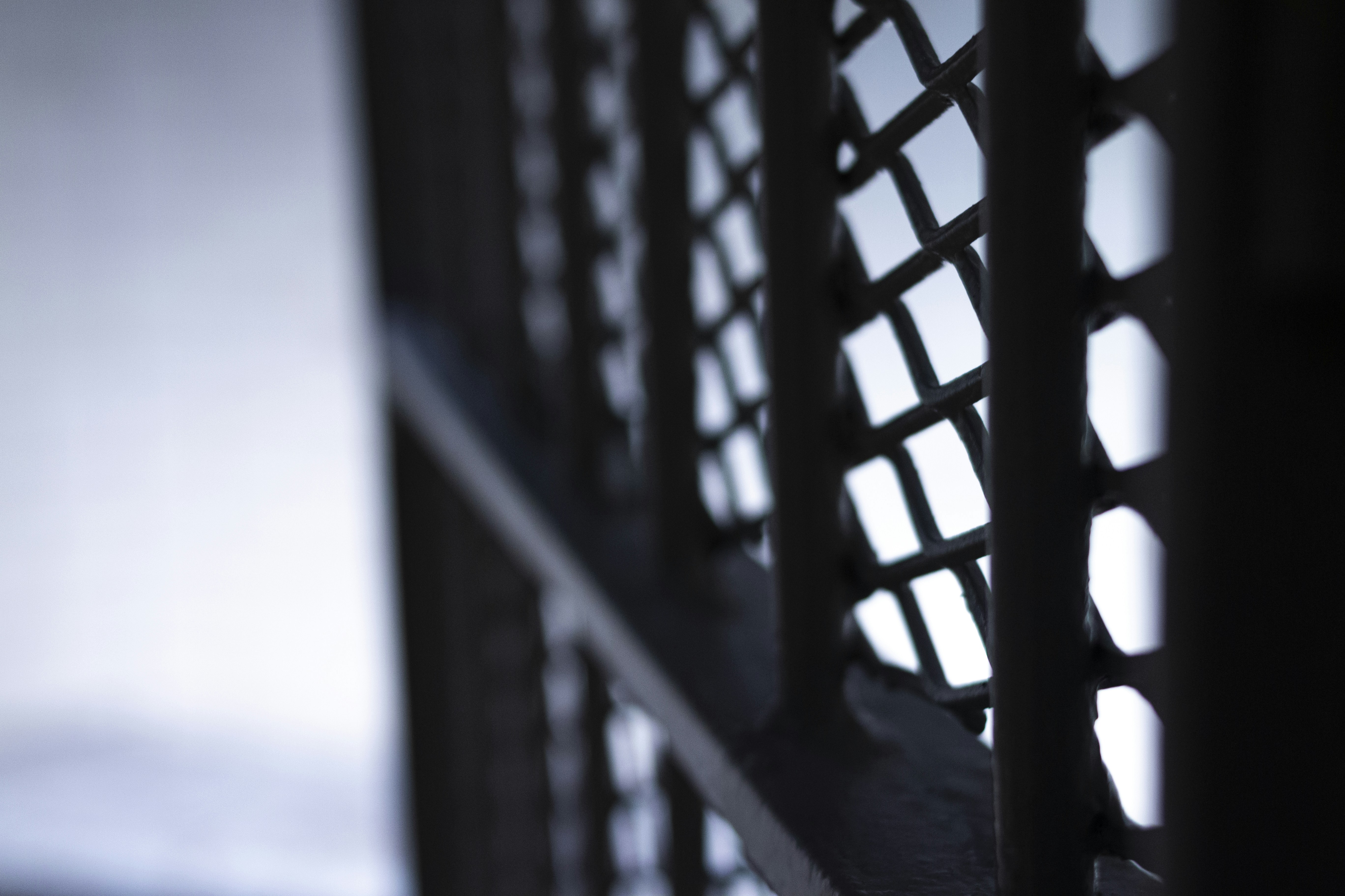 Close-up of a metal grid casting intricate shadows, highlighting the contrast between light and darkness.
