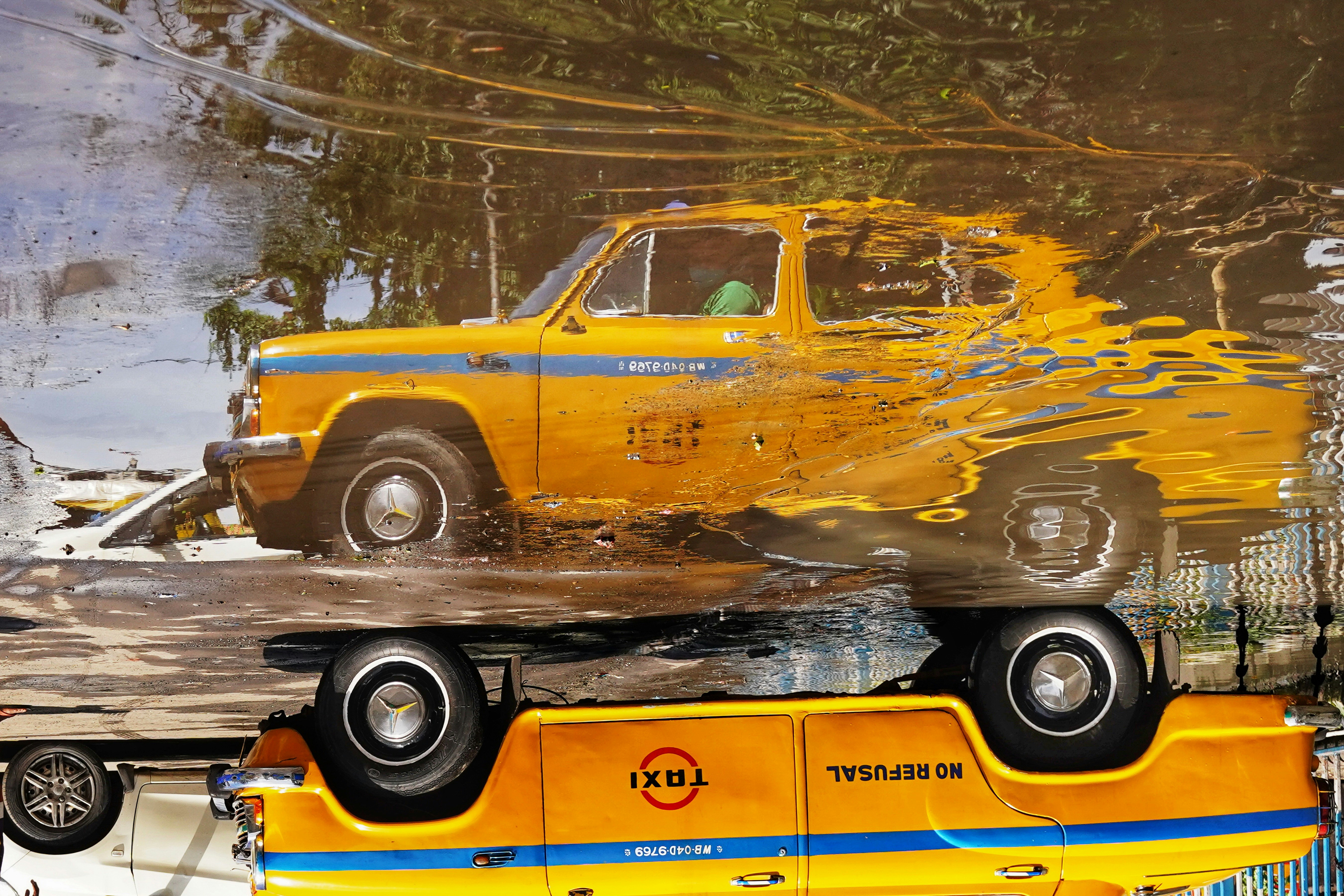 a yellow truck is reflected in a puddle