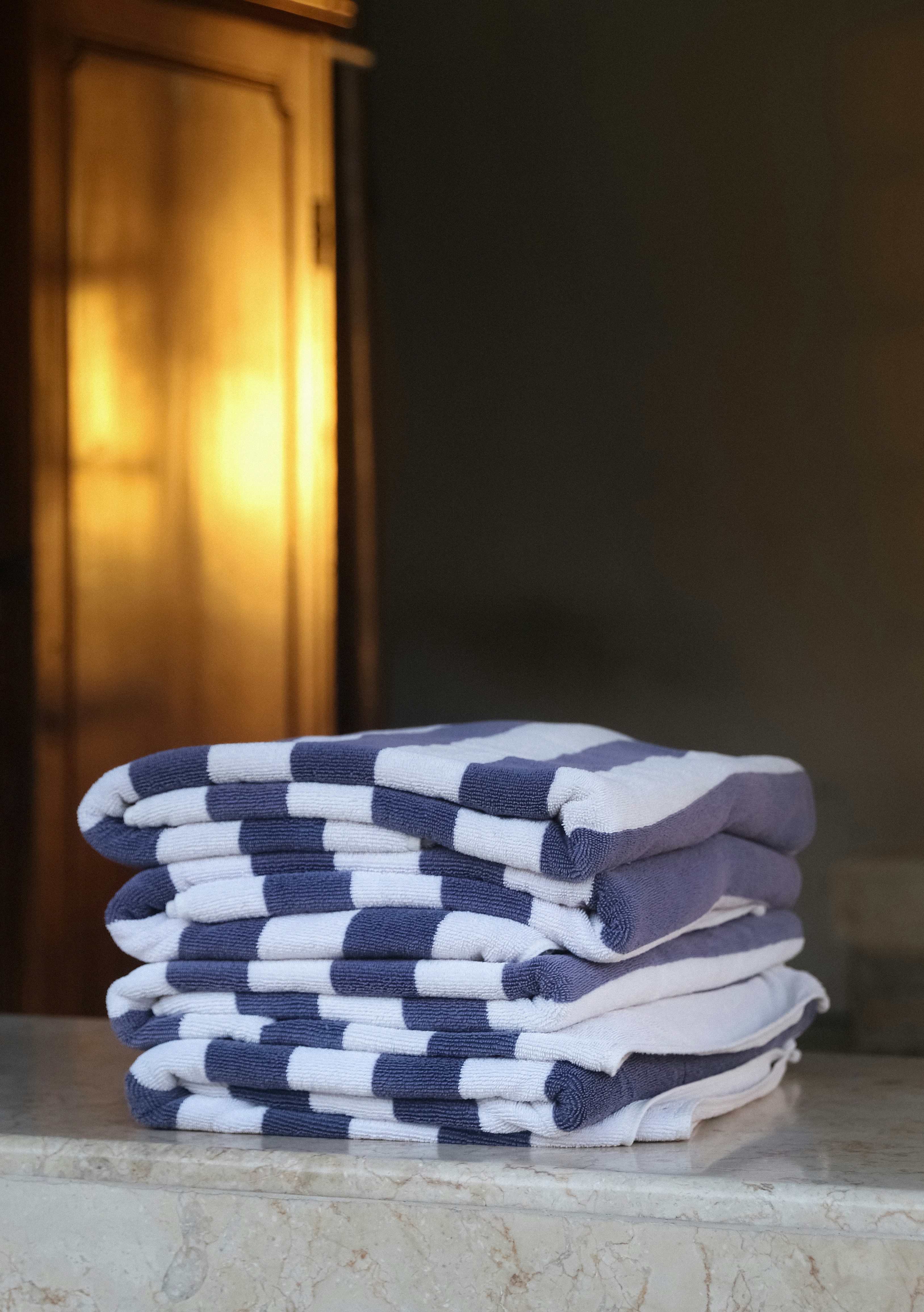 Warm-tinted Still Life: Navy-and-White Towel Stack on Marble Ledge
