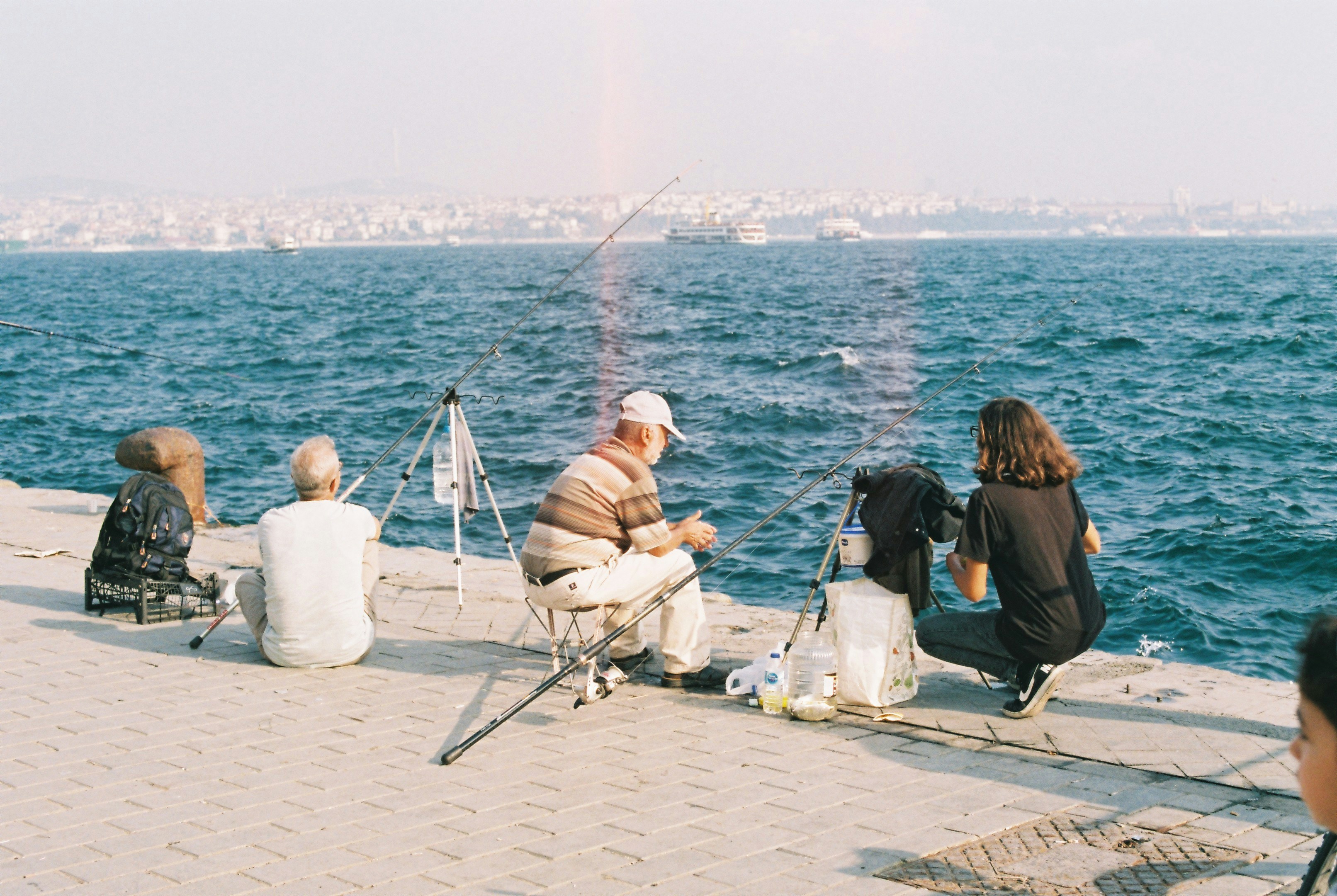 a group of people sitting on the side of a body of water
