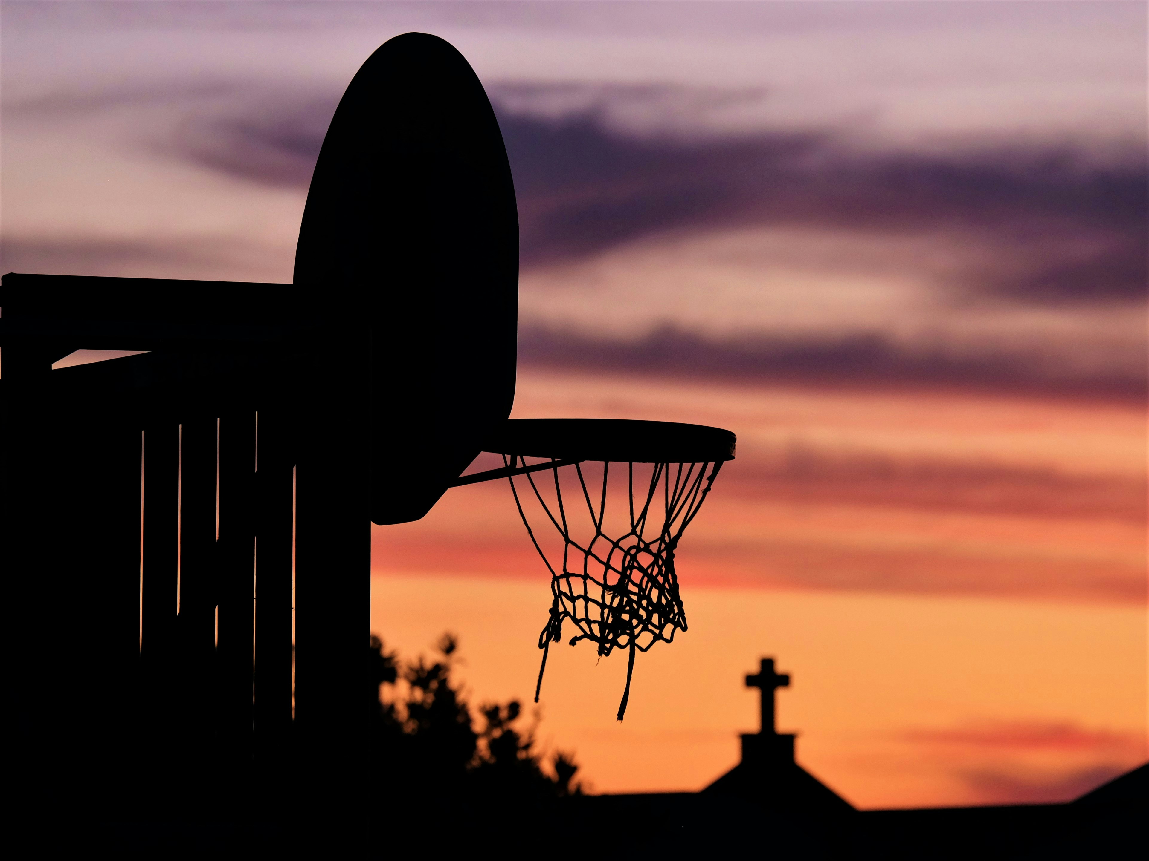 Silhouette at Sunset: A Basketball Hoop and Cross in Quiet Balance