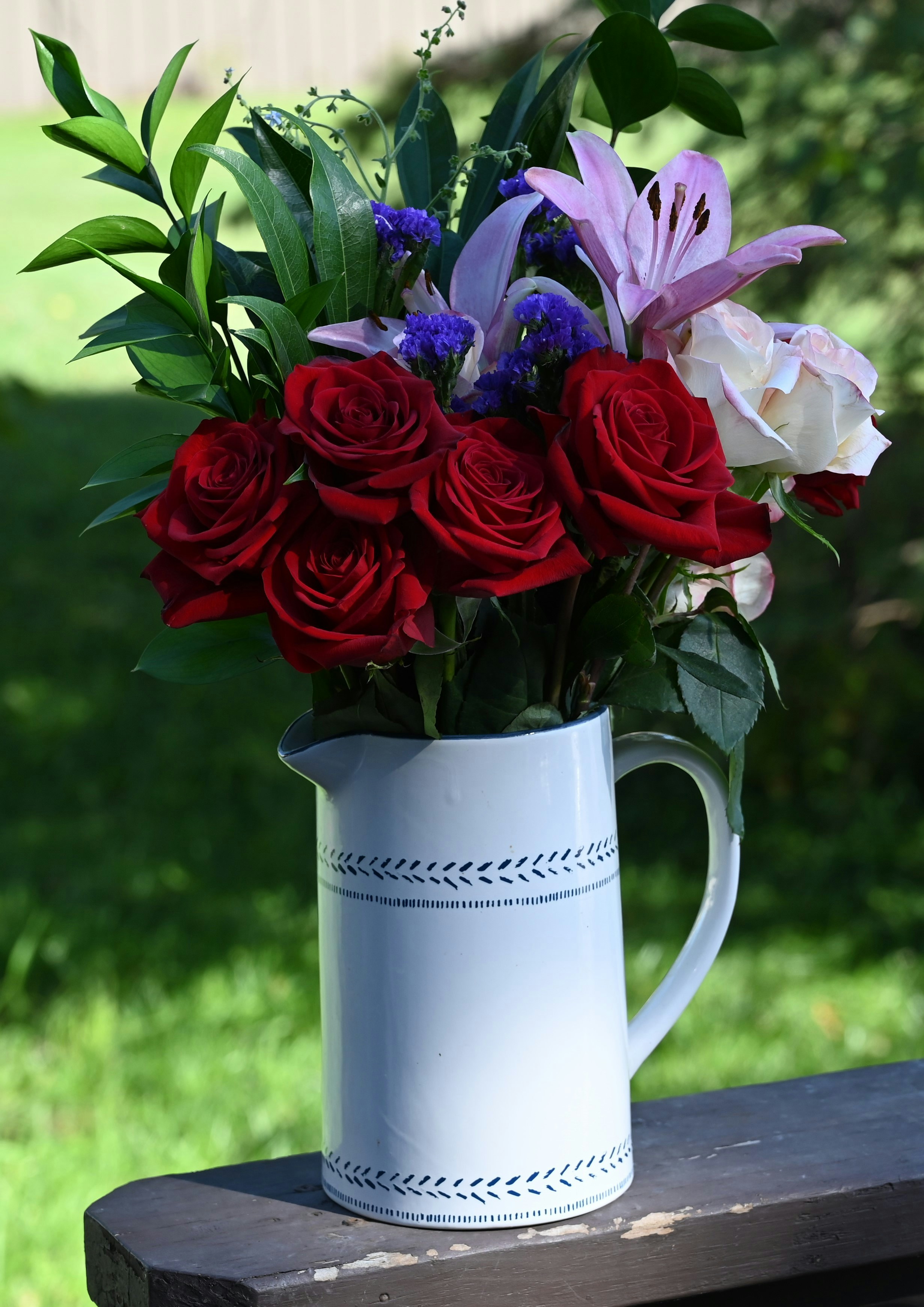 A bouquet of flowers in a white pitcher on a bench photo – Free Capron ...