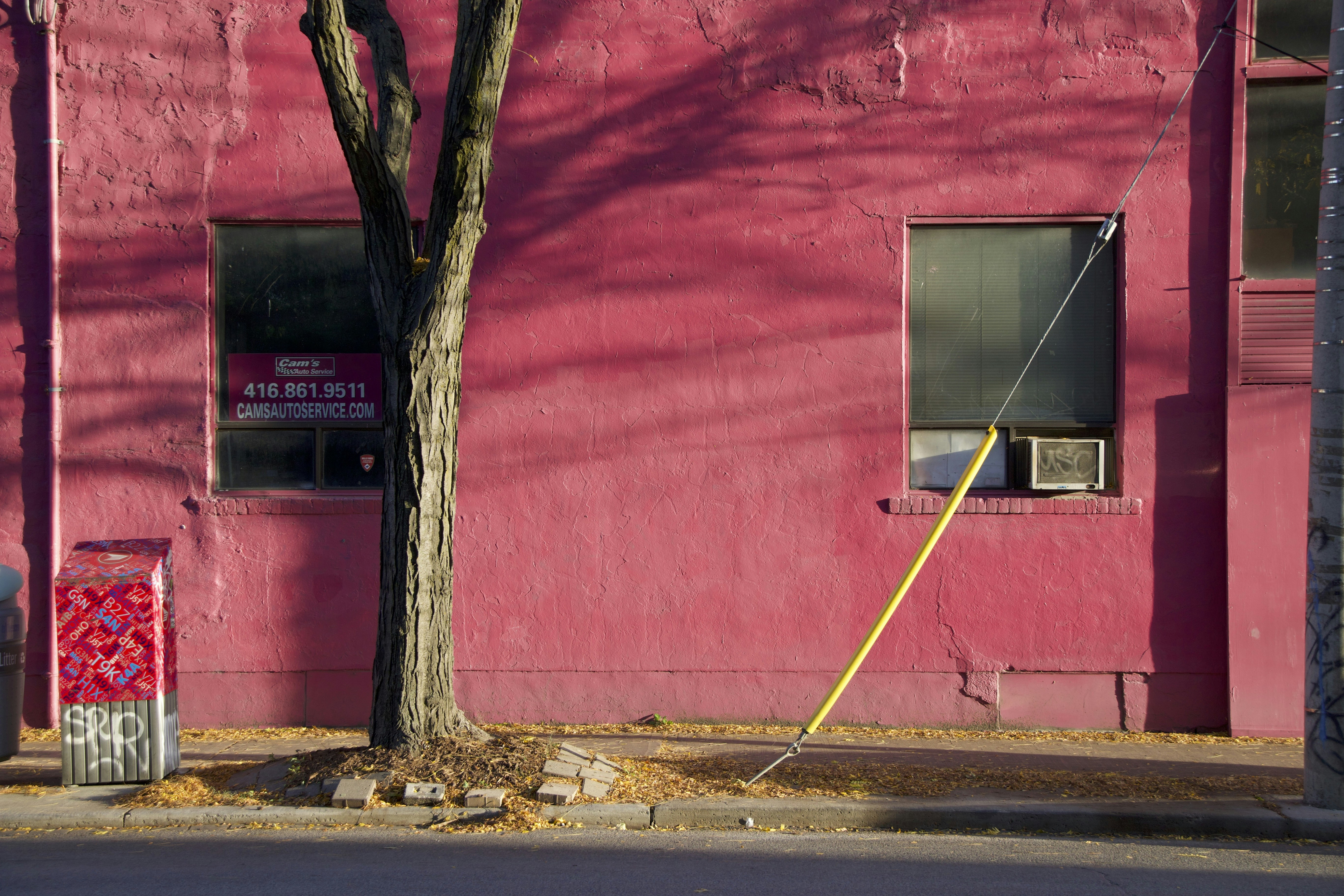 Diagonal Yellow Pole Across a Pink Facade: A Street-Side Study