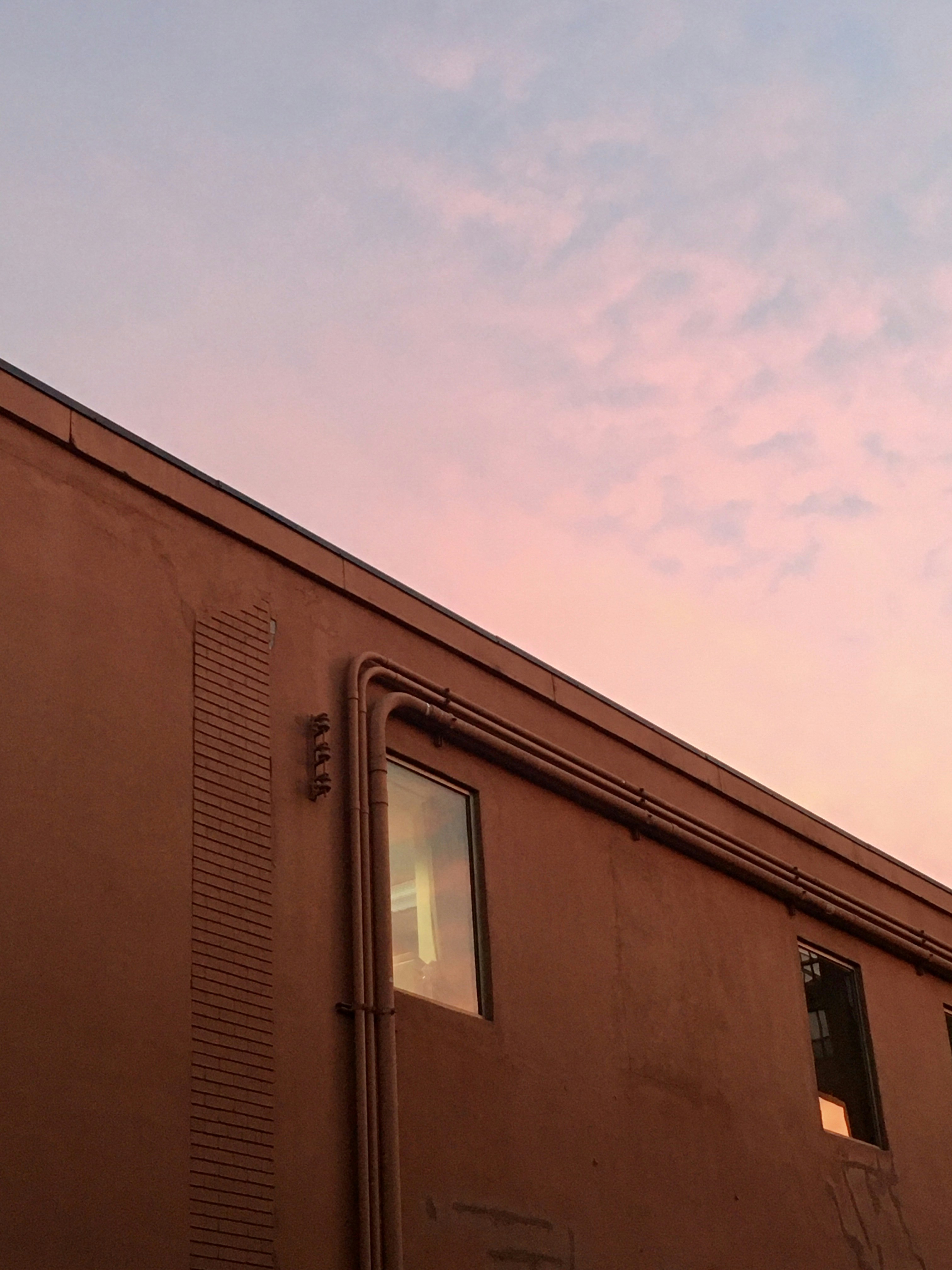 Pastel Dusk over a Corrugated Façade: Pipes and a Reflective Window
