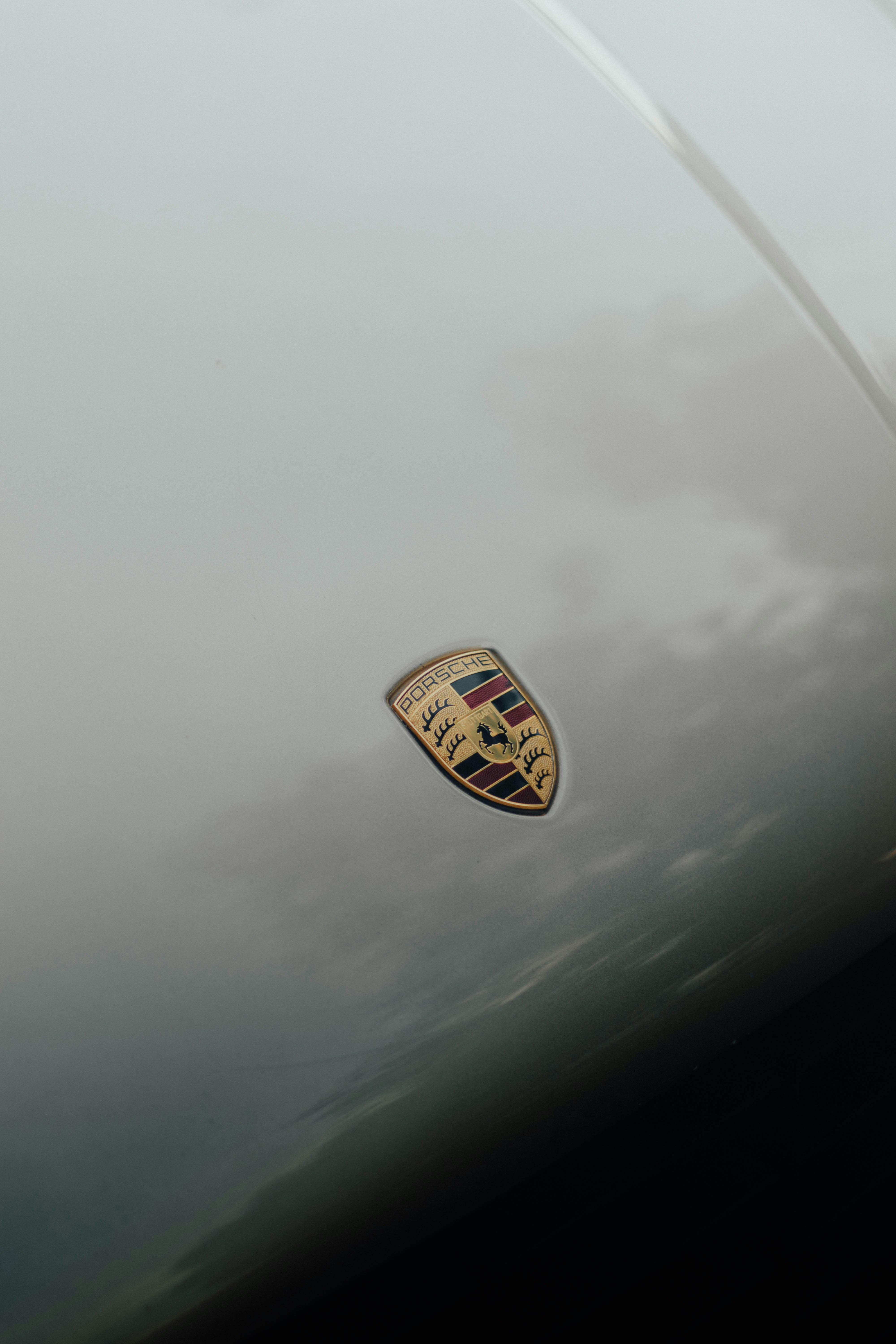 Porsche Crest in Pale Light: Close-Up on a Gleaming Hood