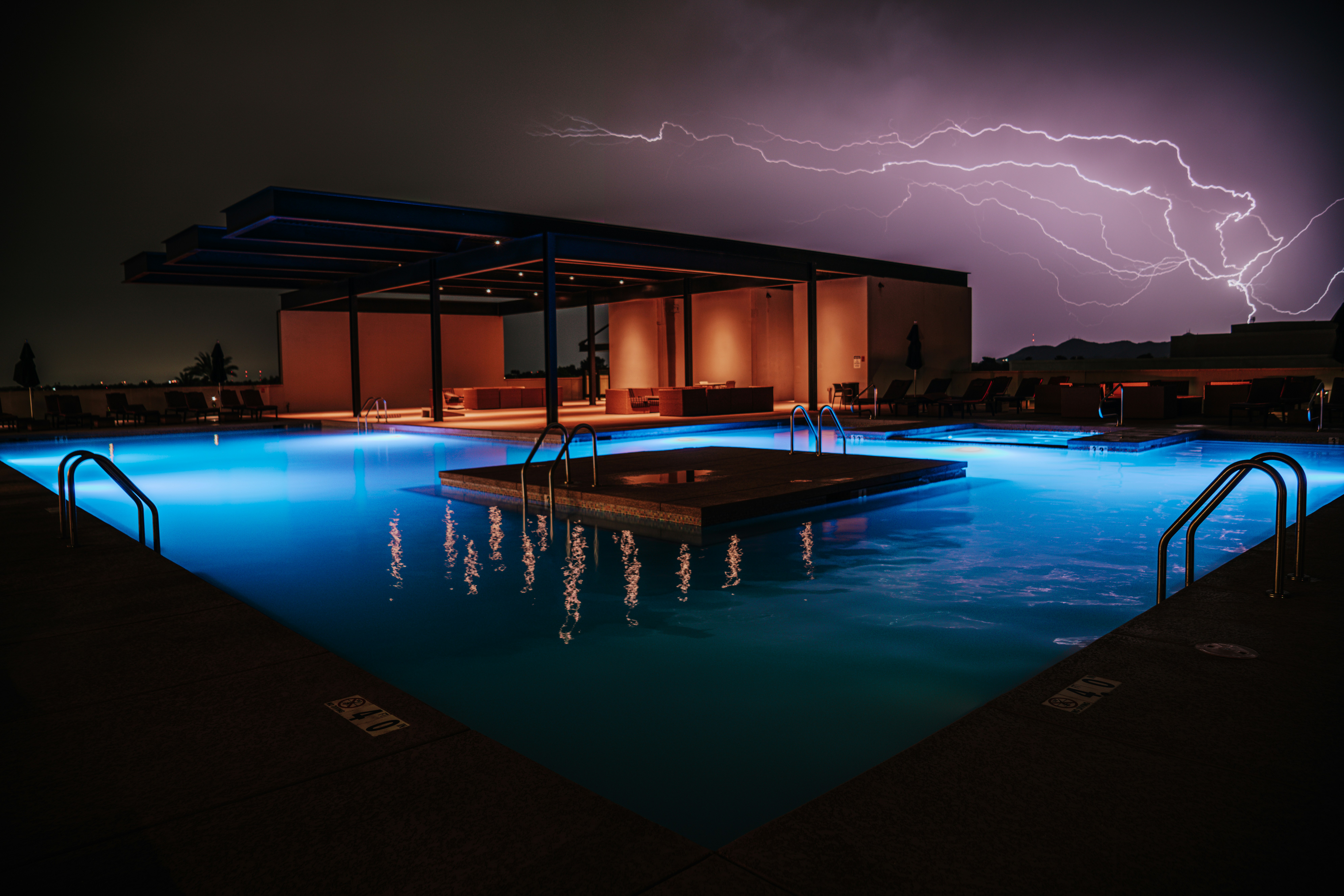 A pool with a lightning storm in the background photo – Free Lightning ...