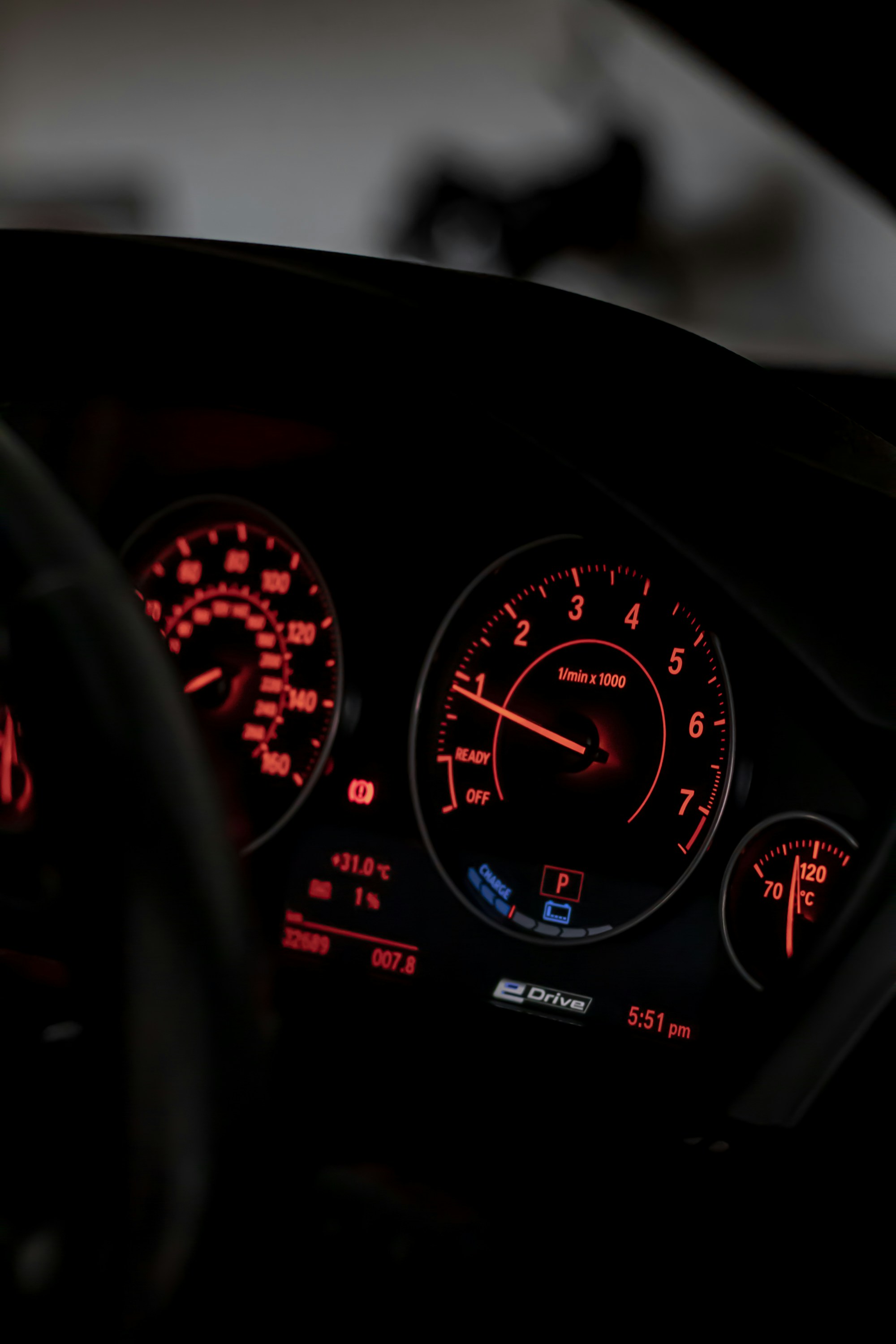 Close-up of a vehicle's dashboard displaying gauges and indicators in vibrant red lighting. The digital clock and temperature readouts enhance the modern aesthetic.