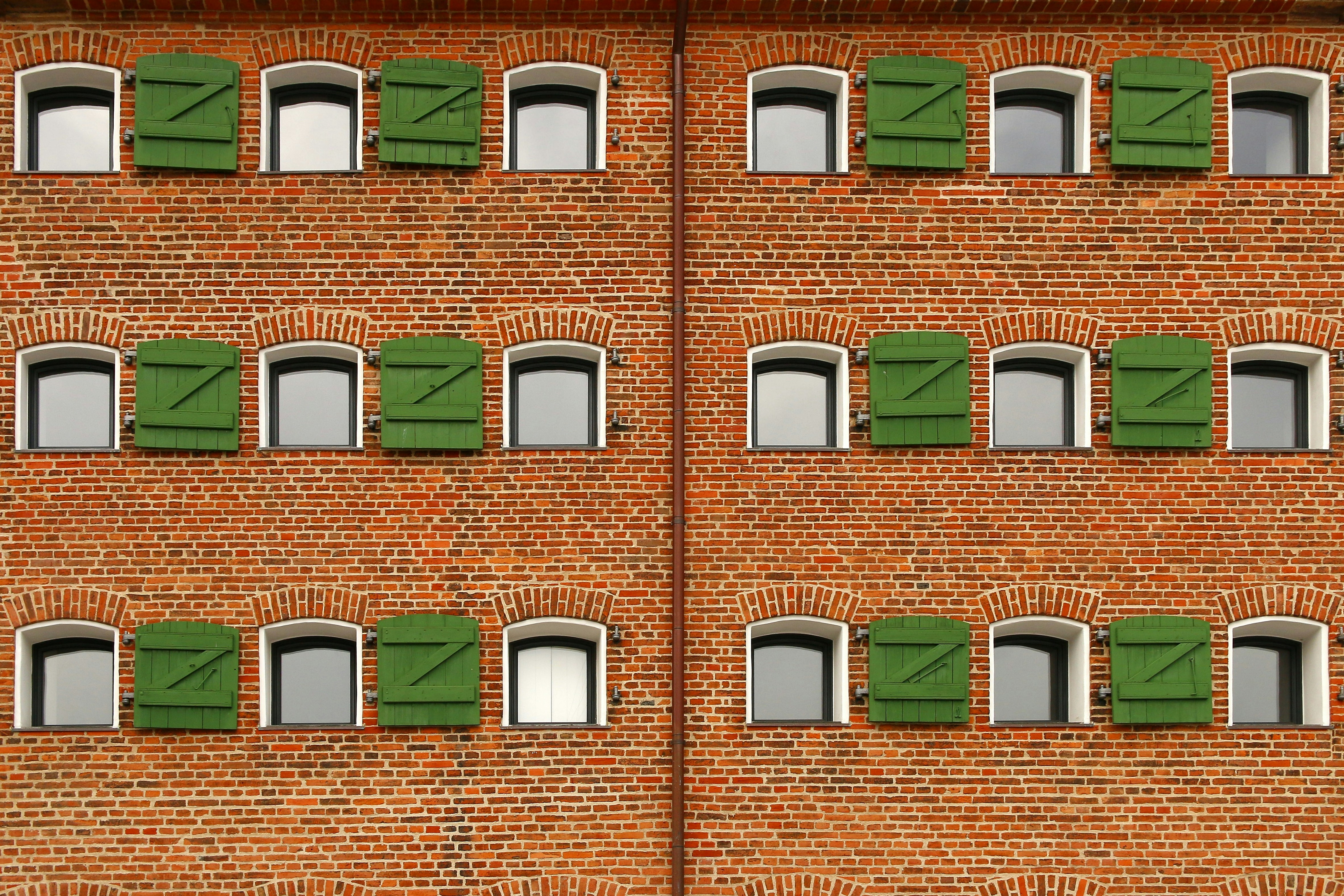 Vertical Seam, Green Shutters: A Brick Facade in Symmetrical Rhythm