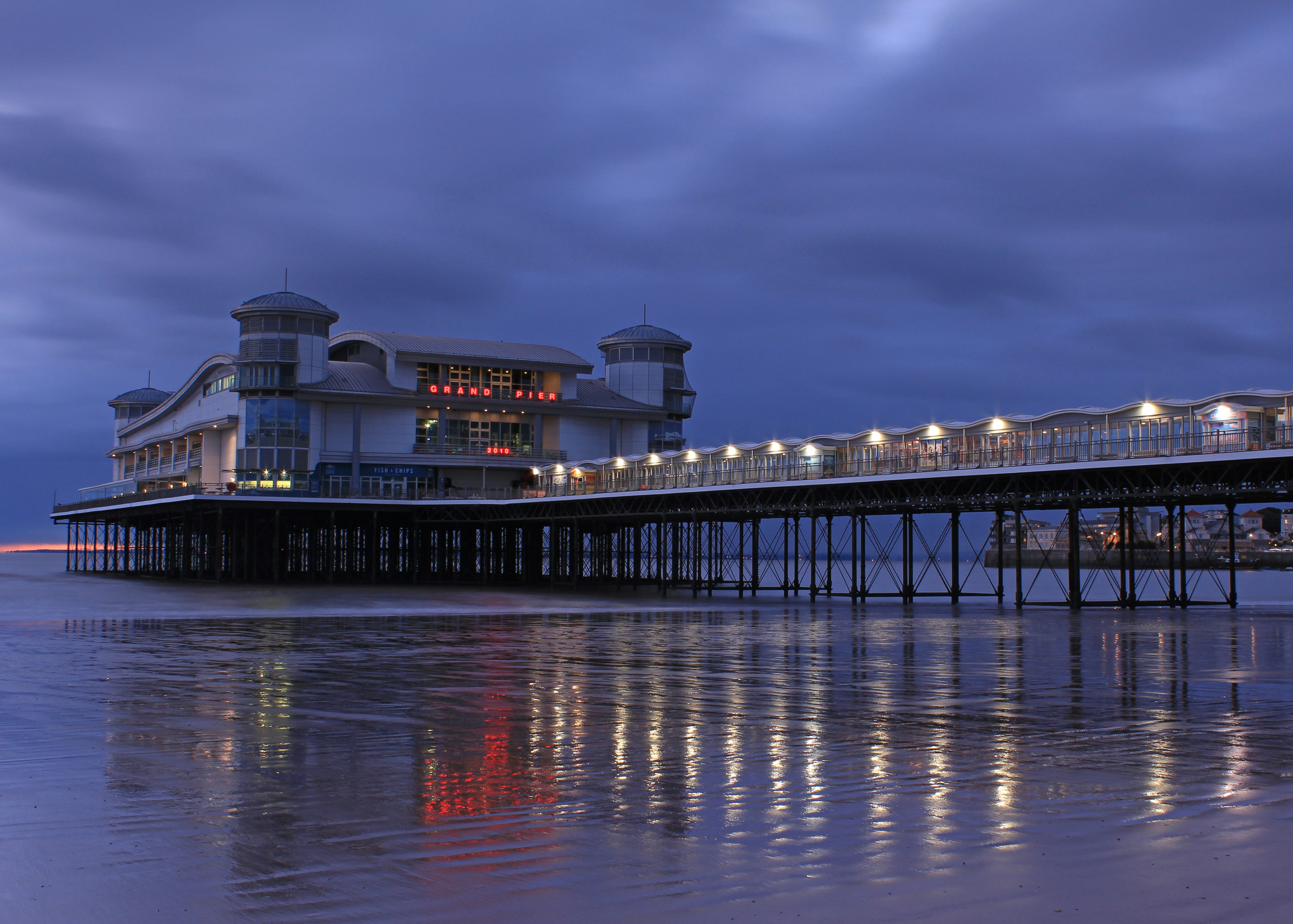 Blue-hour Pierfront: A Modern Building Reaches Over Velvet Waters