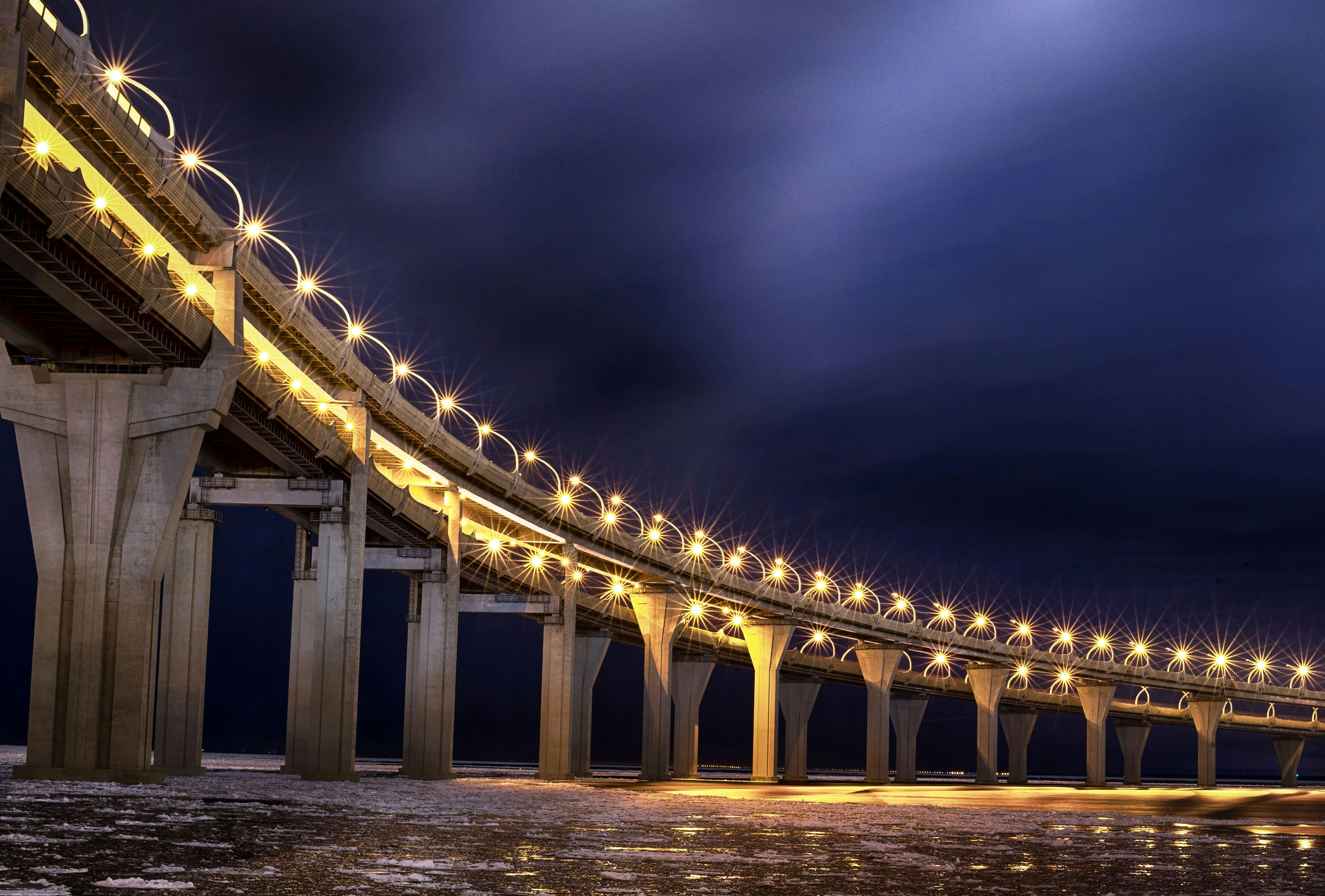 A very long bridge that is lit up at night photo – Free Kanonerskiy ...