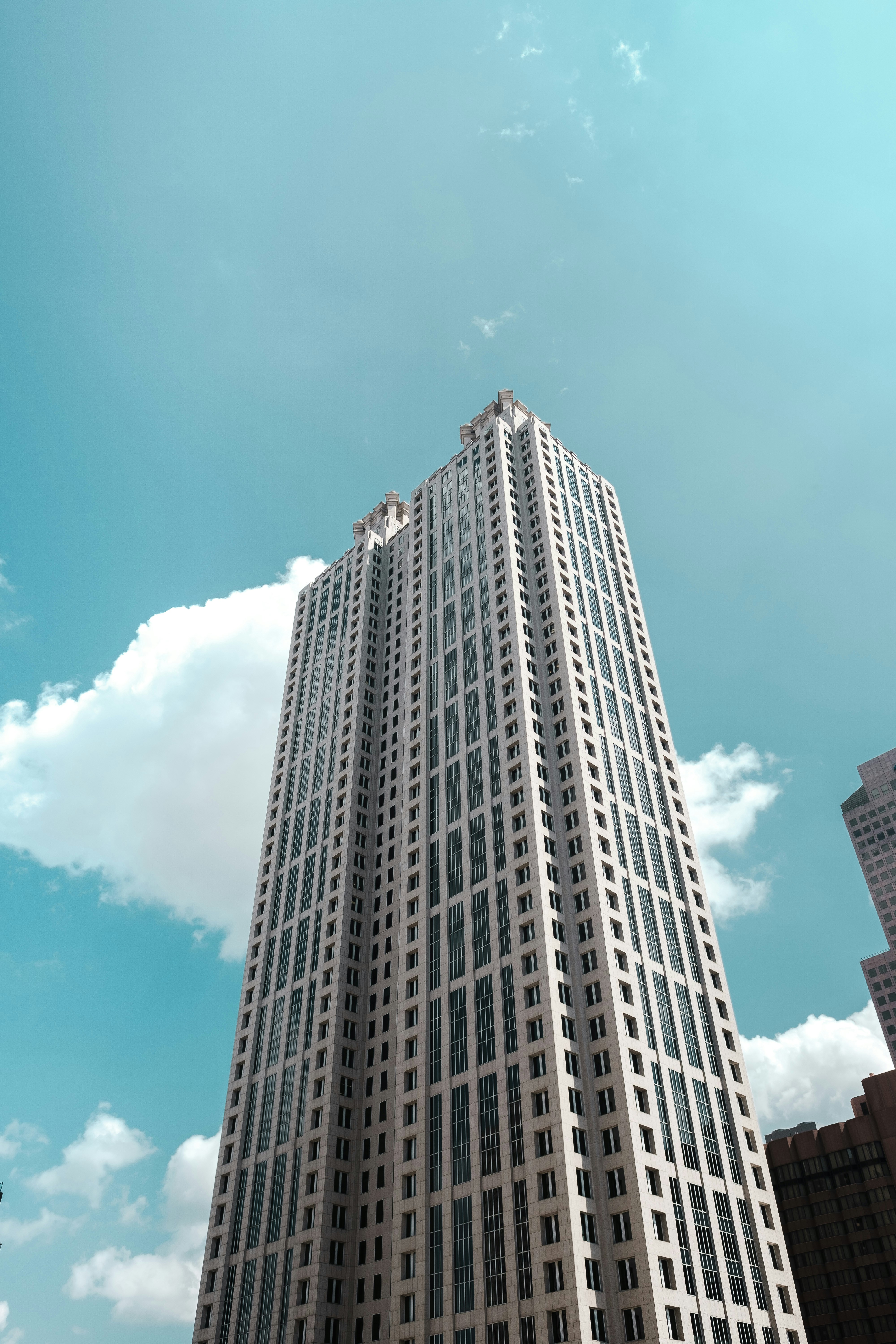 Imposing skyscraper reaching towards a bright blue sky dotted with fluffy clouds.