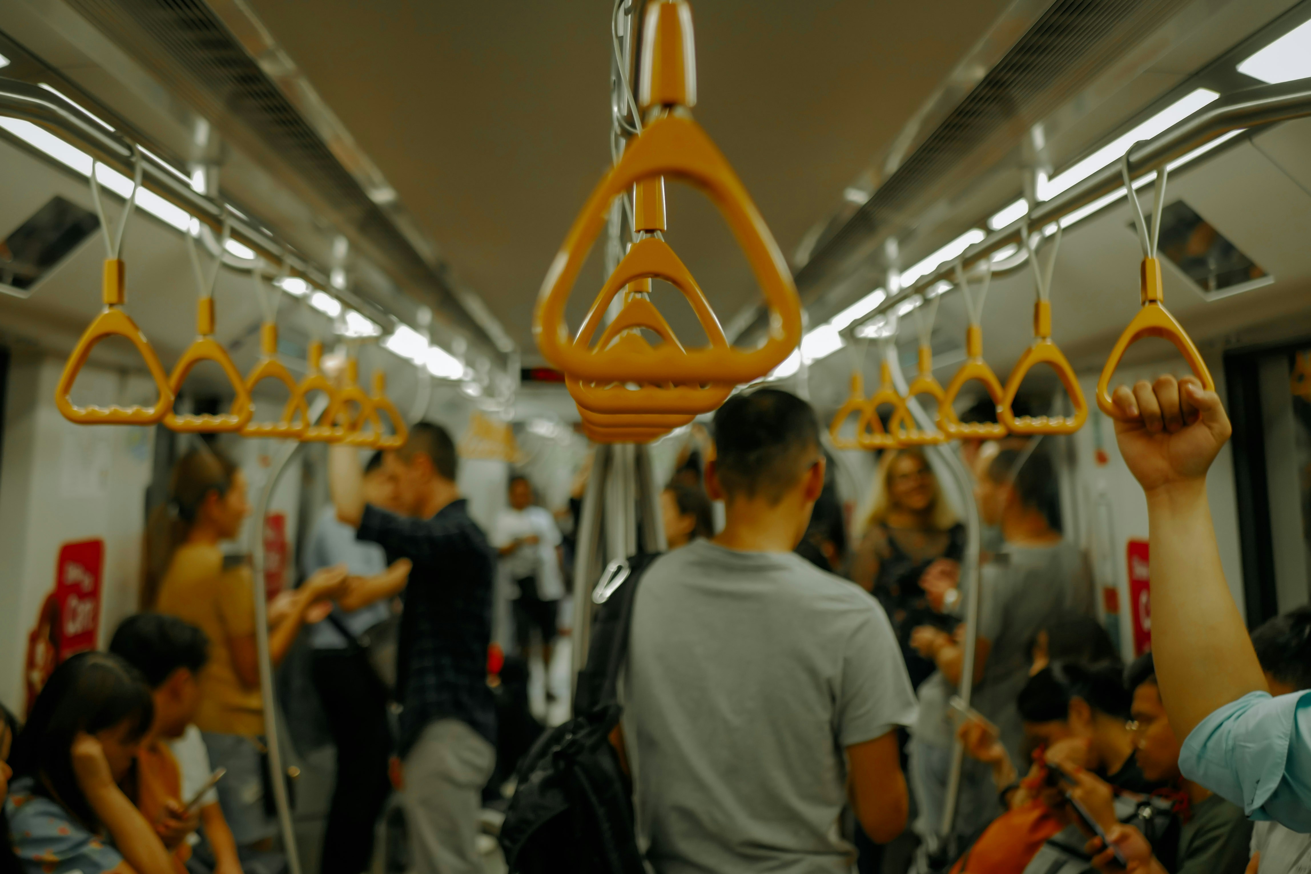 A crowded subway train interior showcasing commuters holding onto overhead straps. The scene captures the essence of urban transportation.