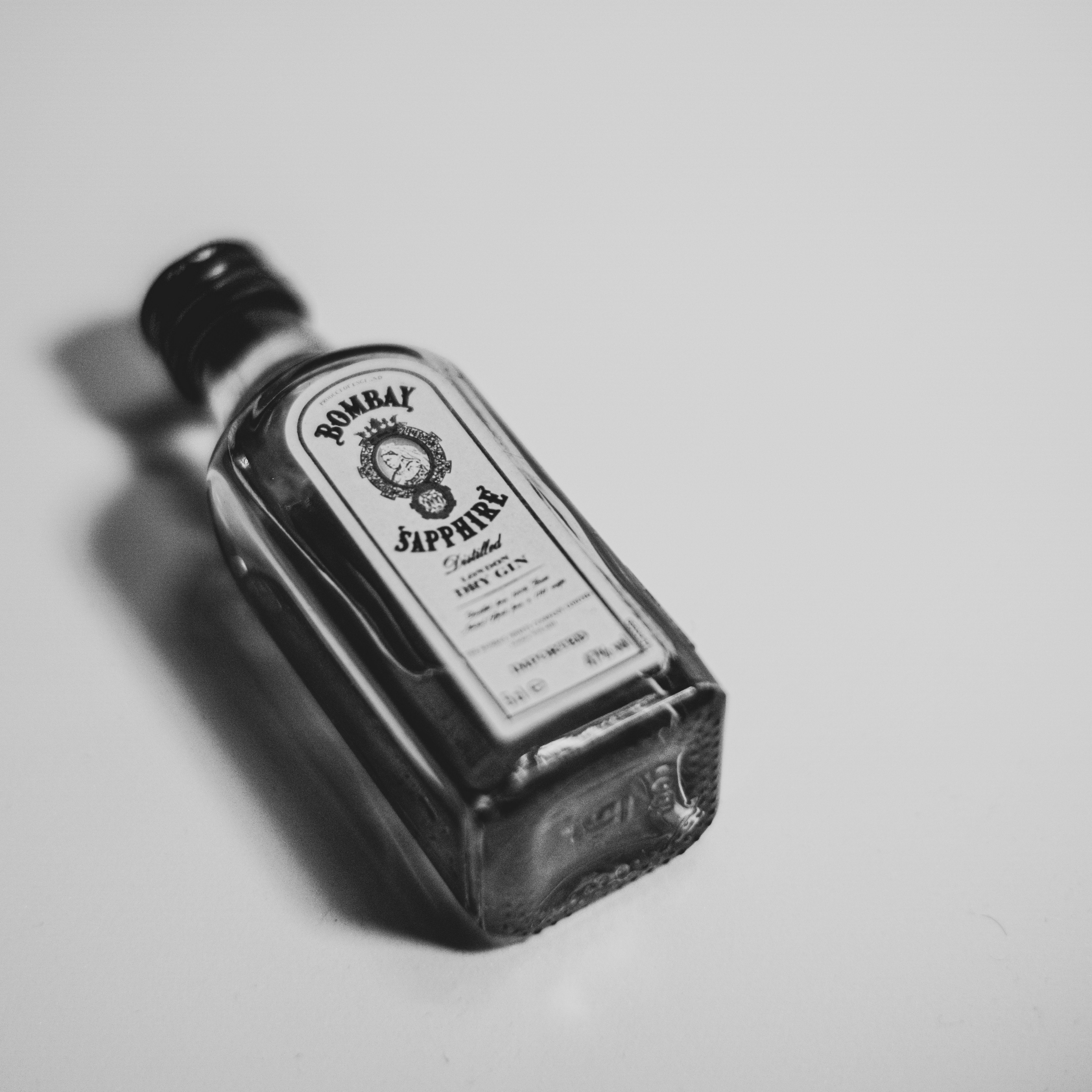 A bottle of Bombay Sapphire gin elegantly positioned on a white surface, showcasing its classic label and refined design.