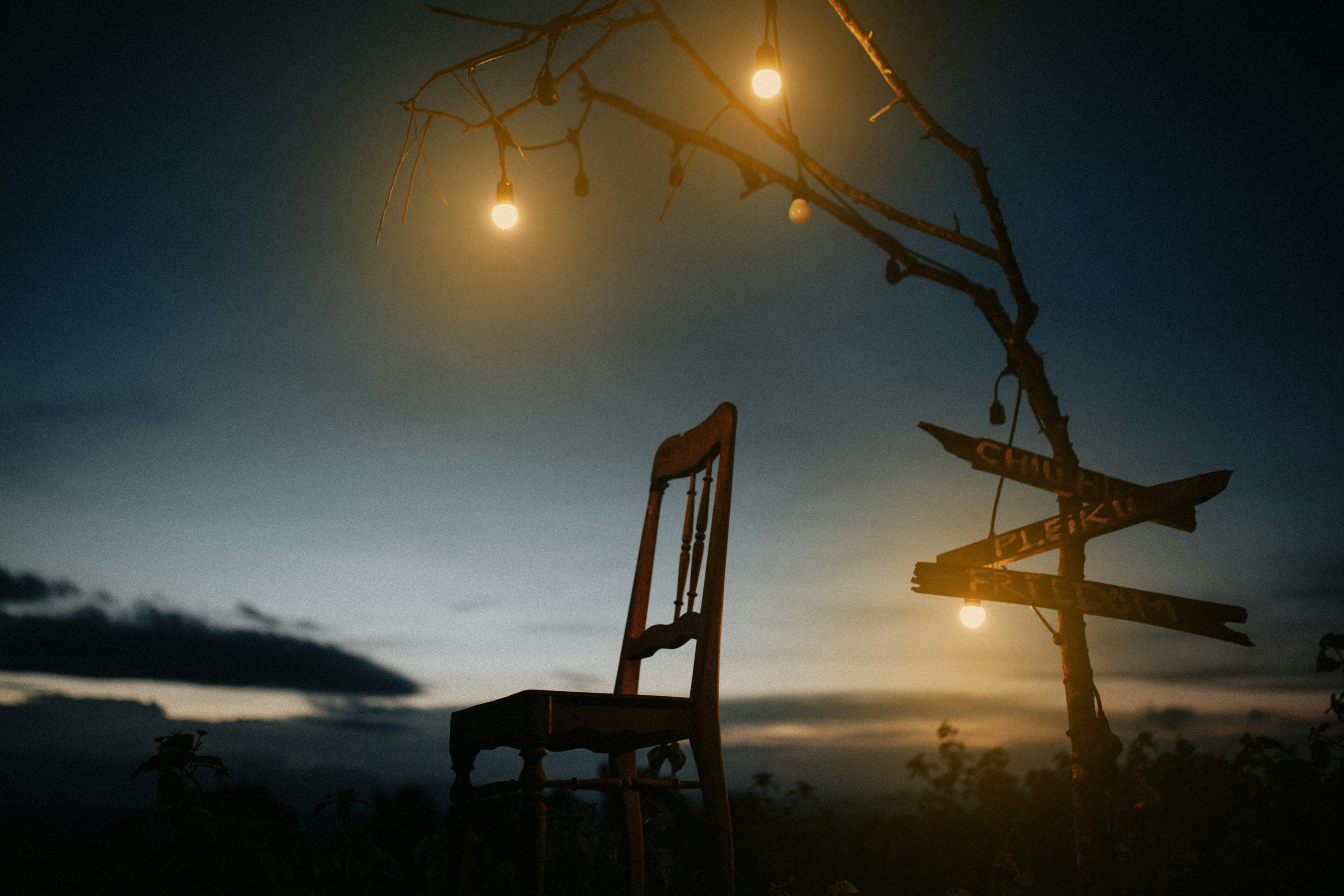 Lone Chair Beneath Flickering Orbs at Dusk