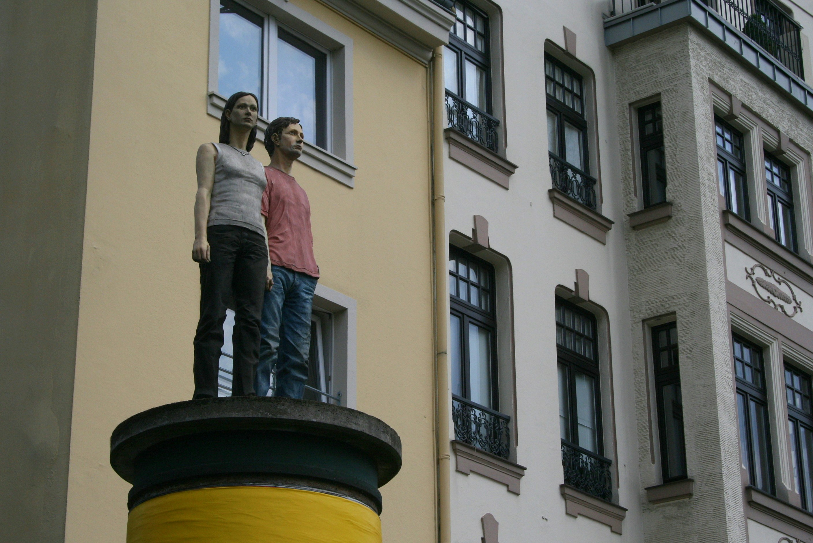Figures on a Round Pedestal Overlooking a City Facade