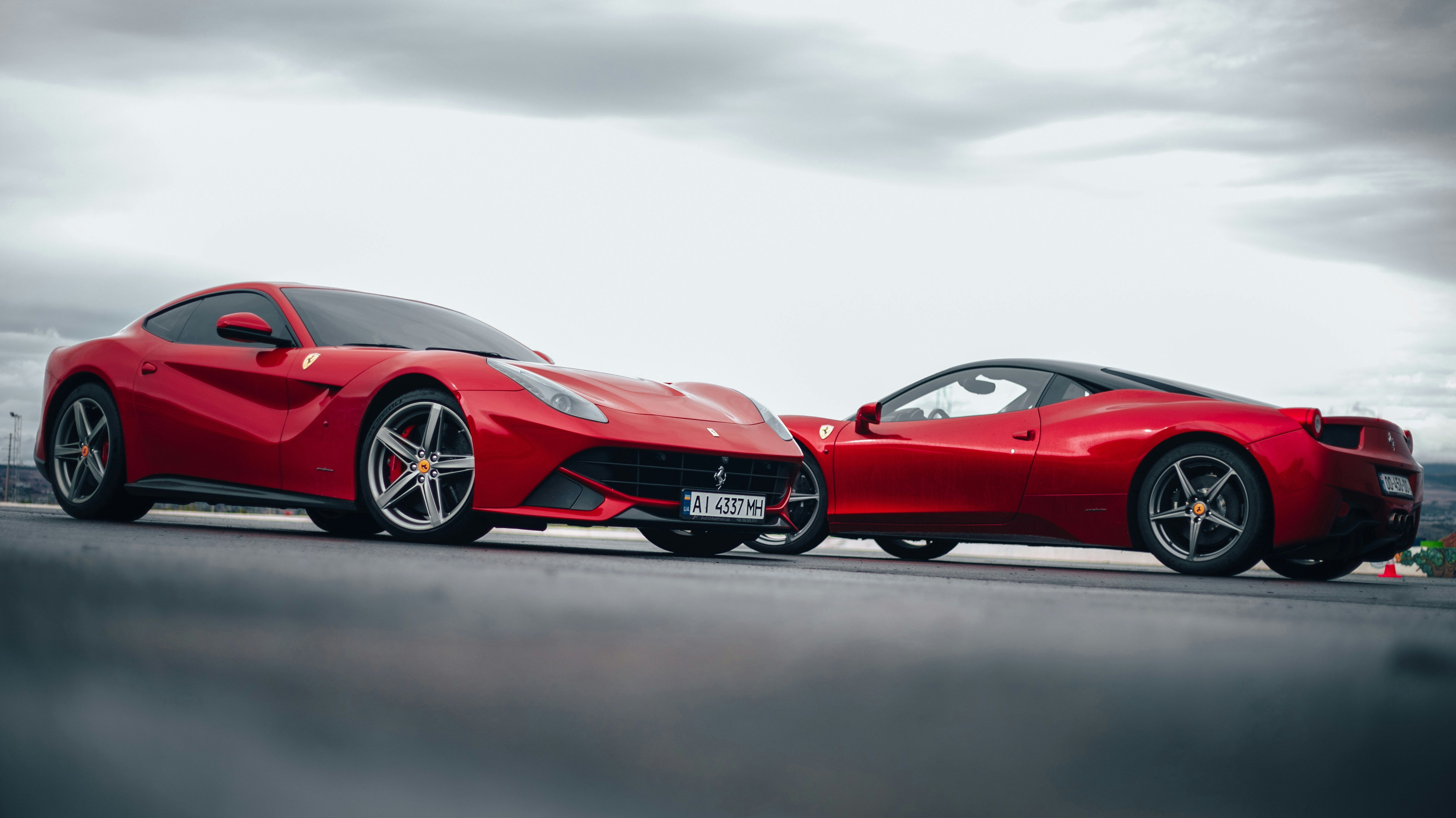 Twin Scarlet Ferraris Idle on a Cloud-Grade Gray Runway