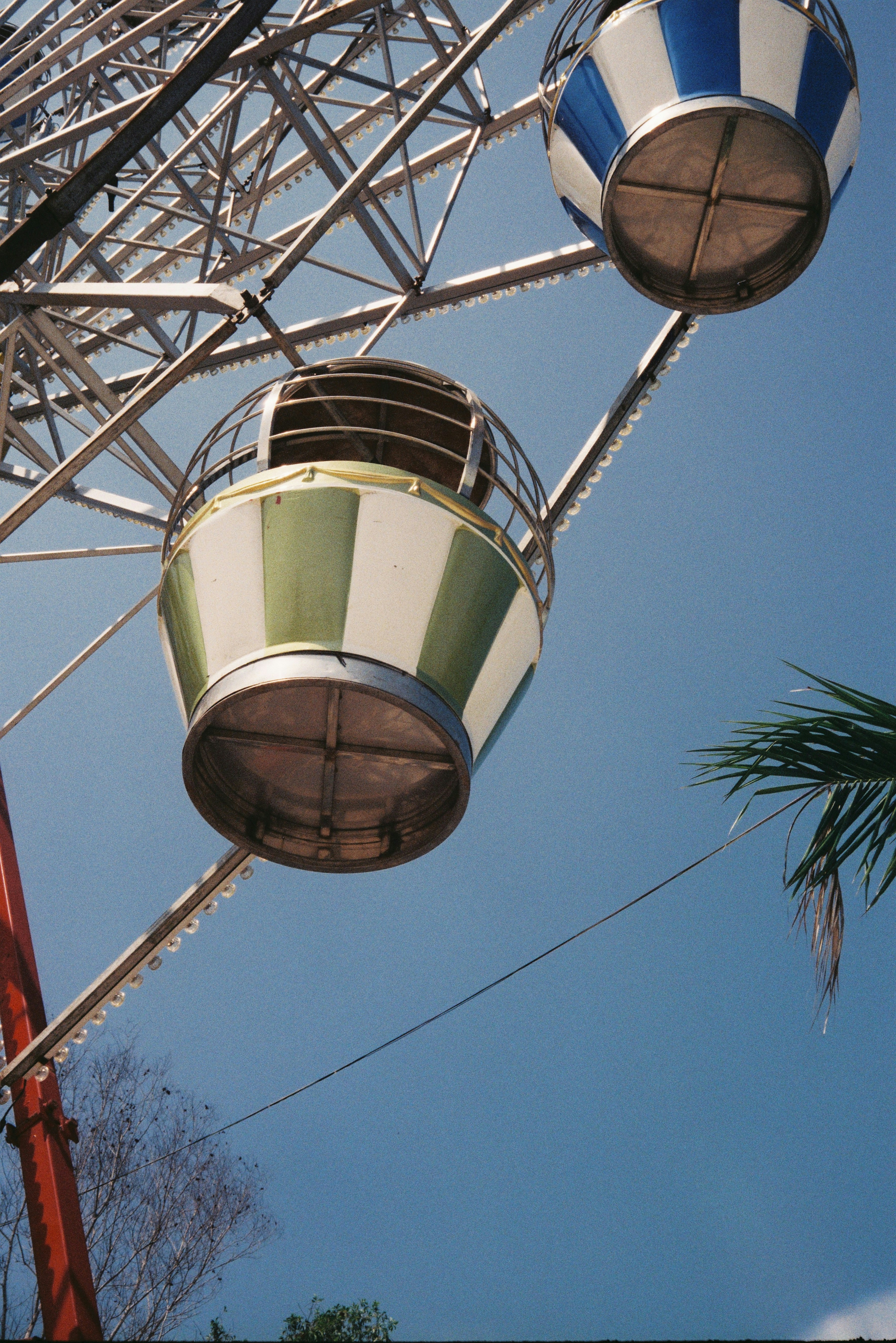 Colorful gondolas of a Ferris wheel against a clear blue sky, showcasing a playful amusement park atmosphere.