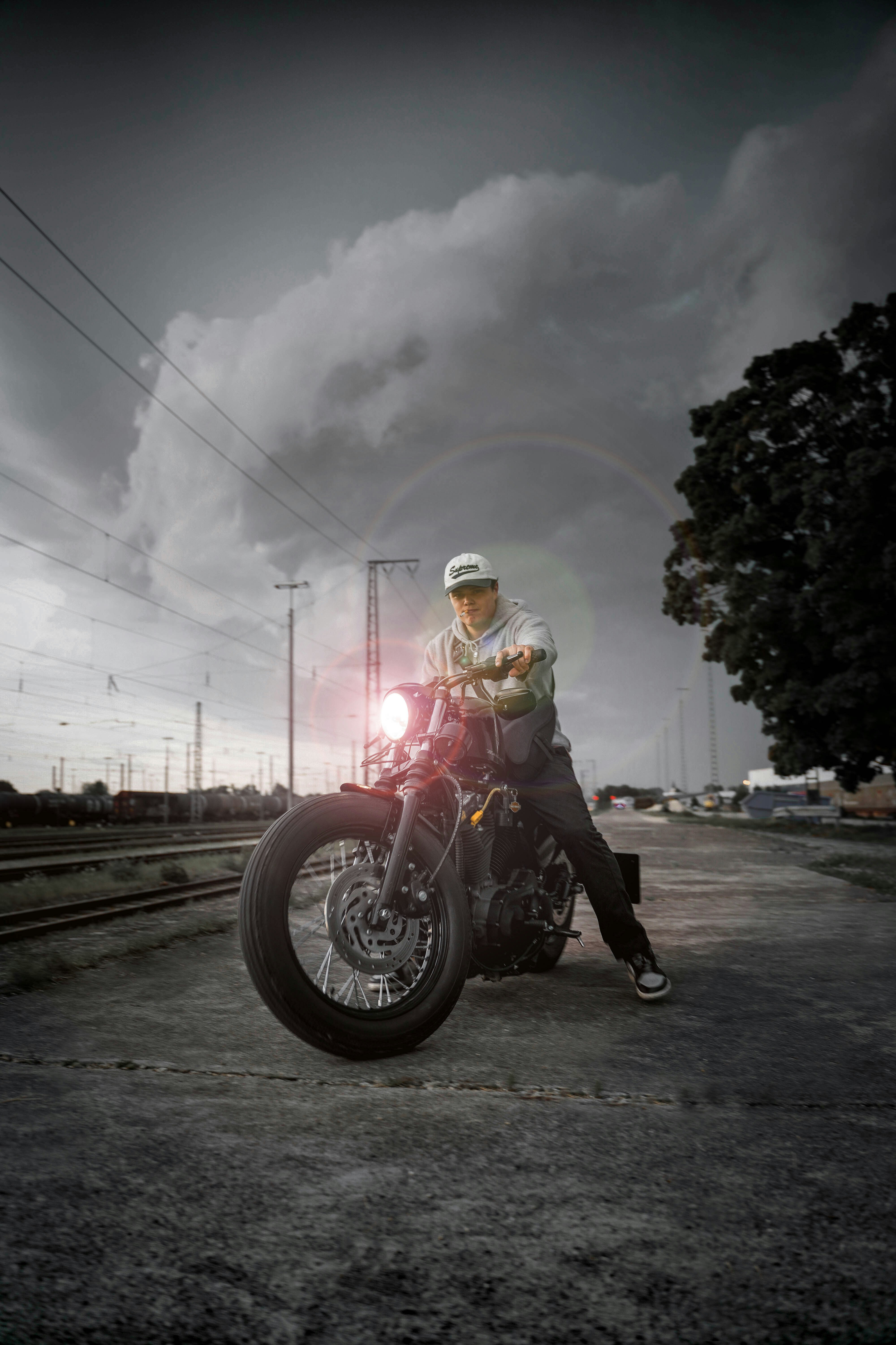 Motorcyclist on a powerful bike poised on an industrial road beneath dramatic cloud formations.