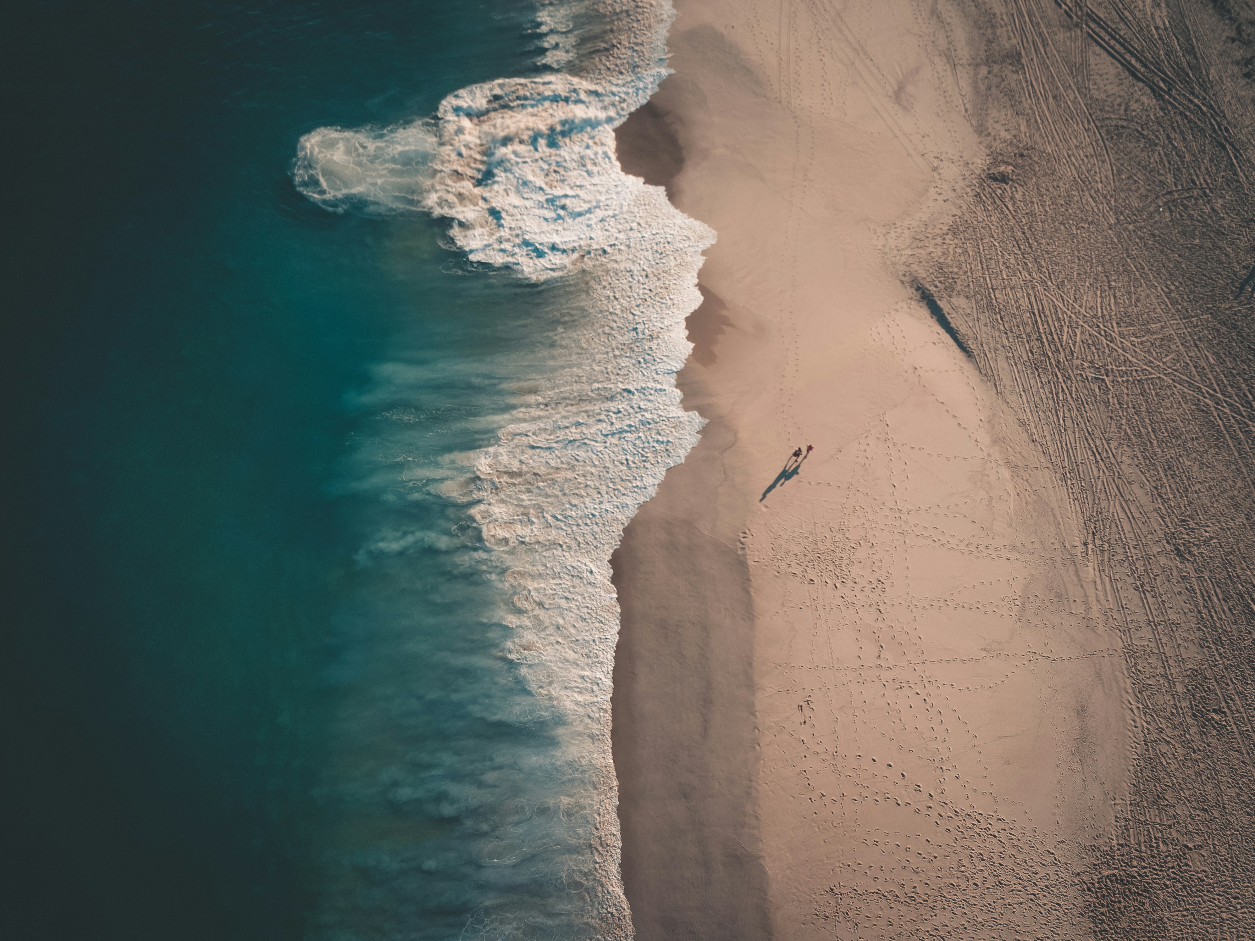 Aerial view of gentle ocean waves meeting a serene sandy beach.