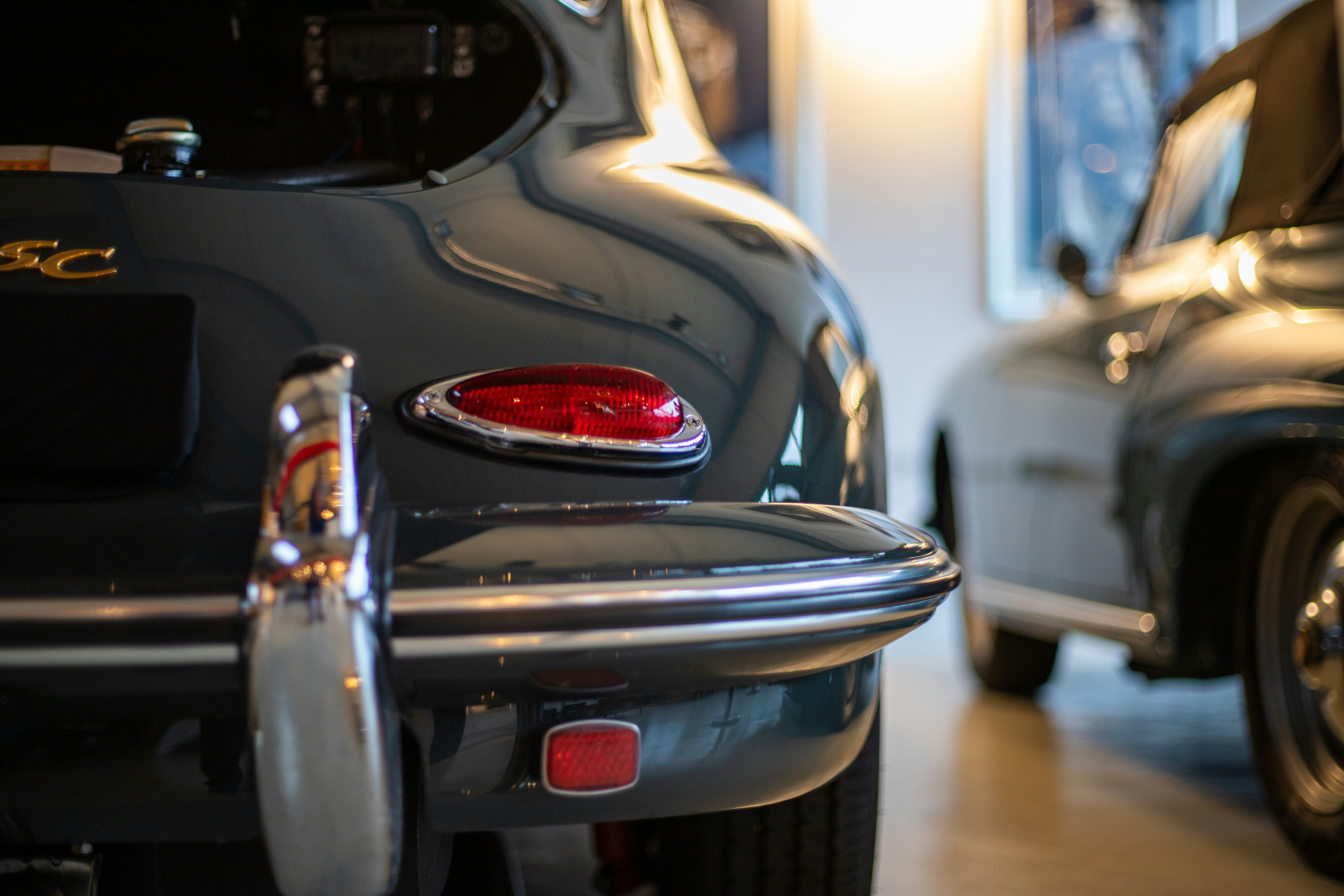 Chrome Echoes: Teal Vintage Tail Light in a Quiet Showroom