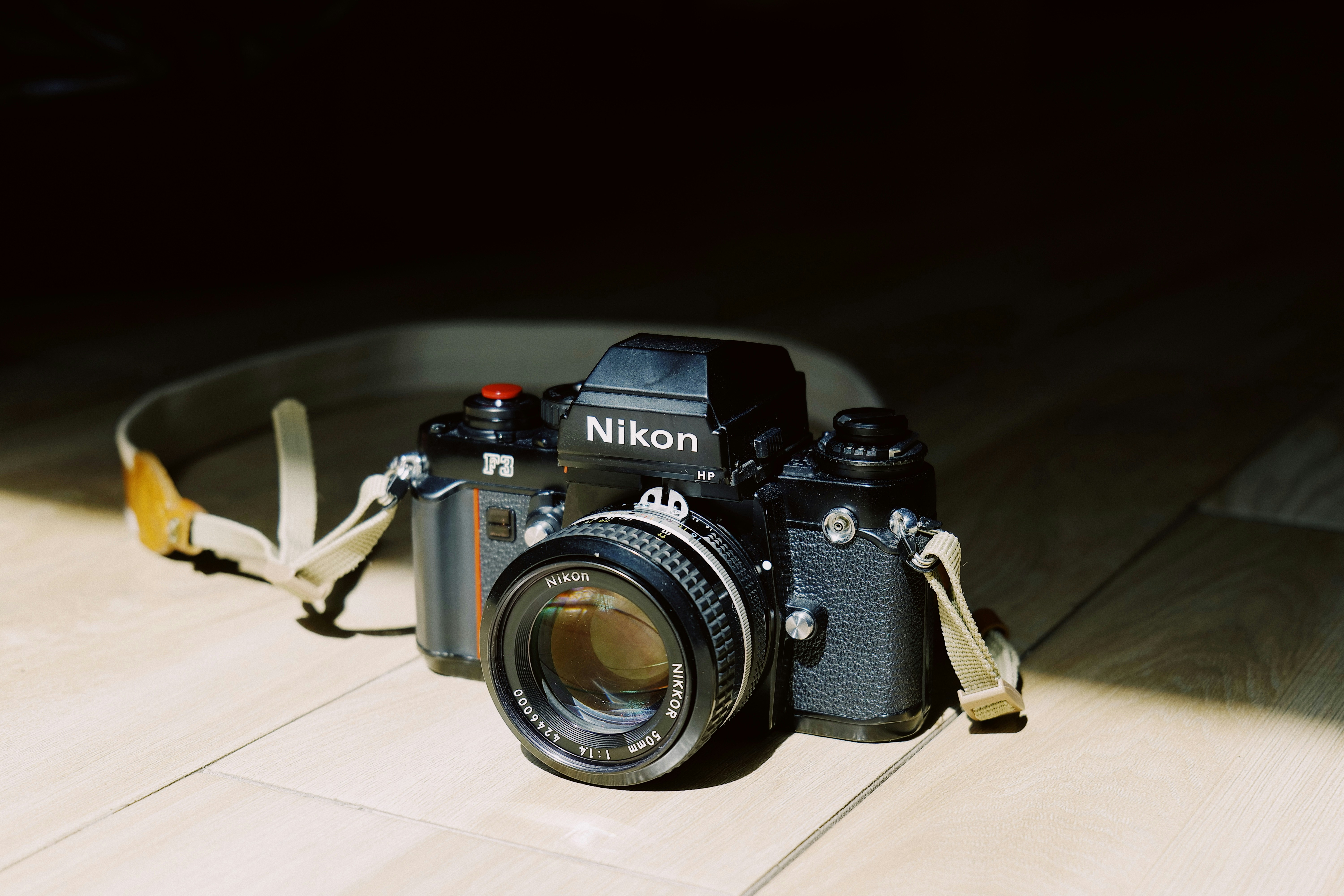 Film | a camera sitting on a wooden floor with a strap around it
