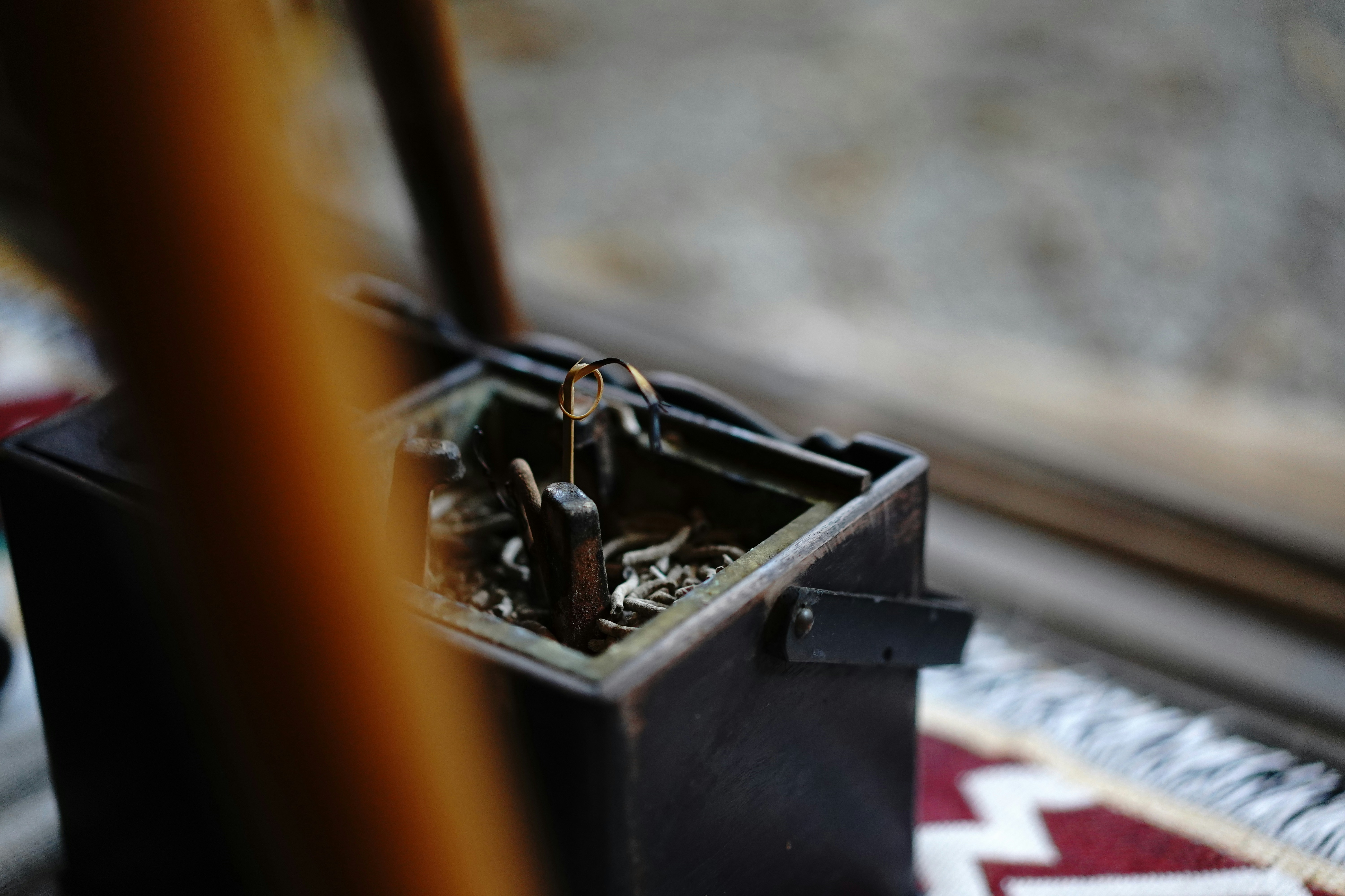 An intricately designed wooden box filled with natural materials, resting on a colorful woven rug, evoking a sense of heritage and artistry.