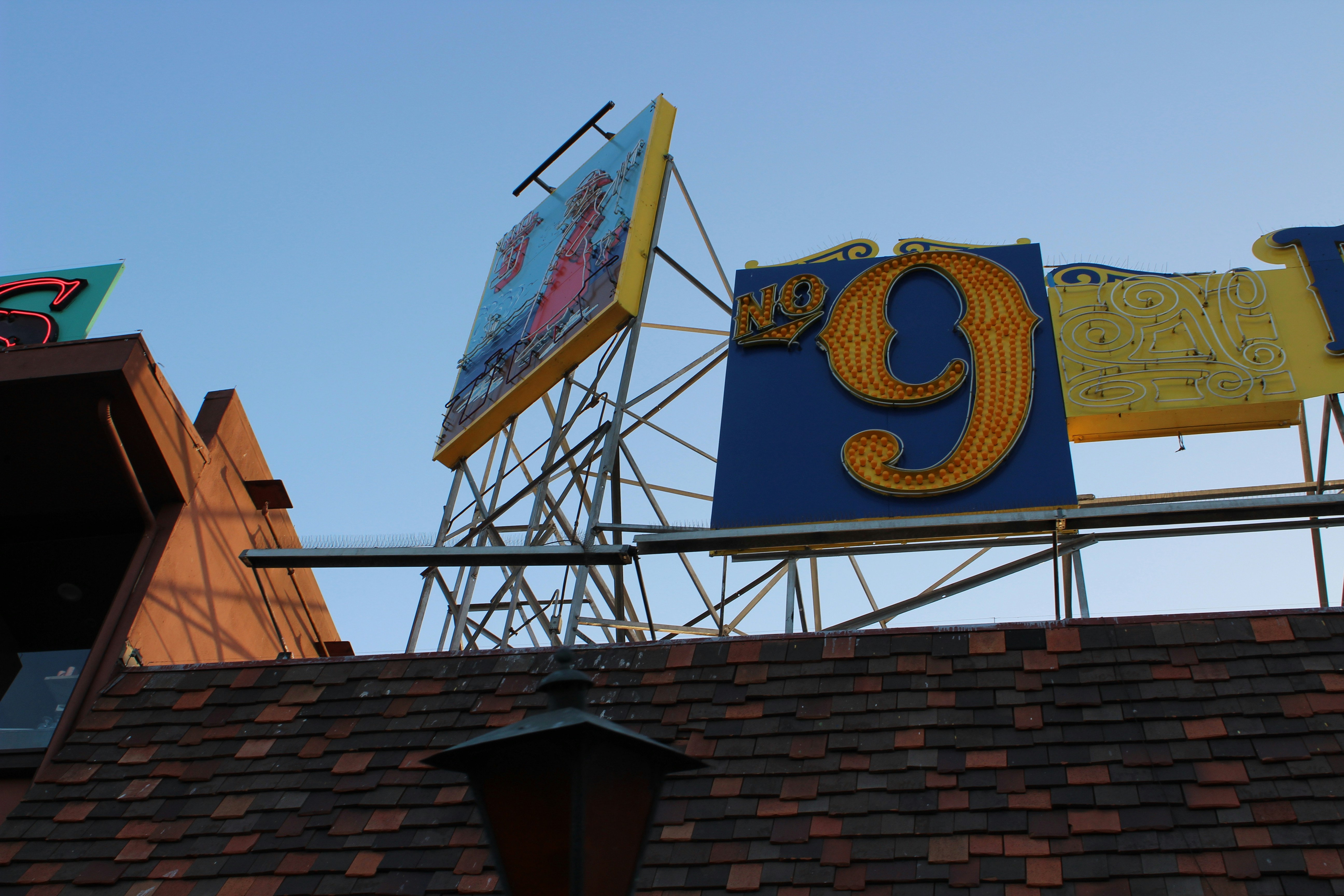 The Ninth Sign Over a Shingled Rooftop Against a Clear Sky