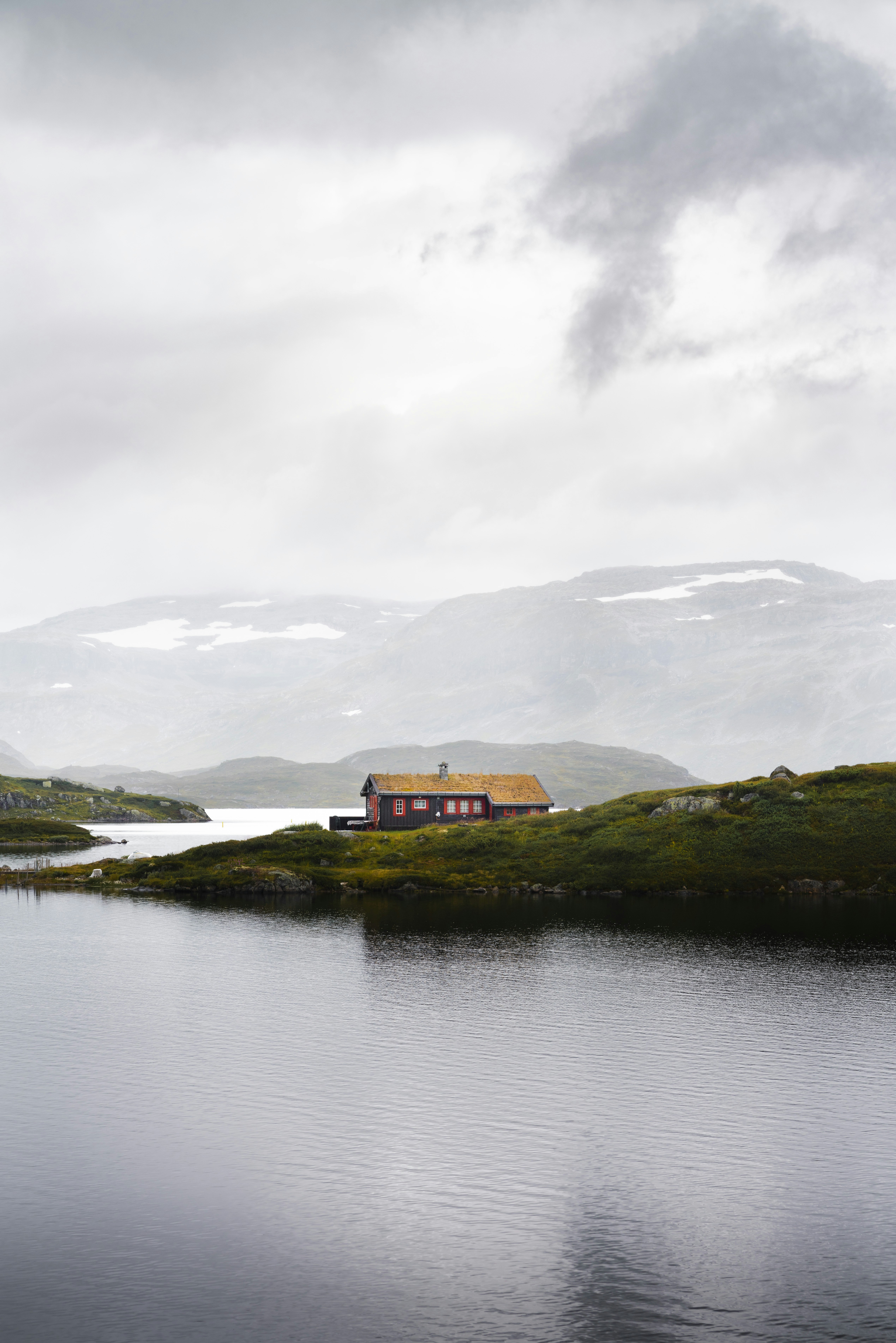 Red-Roofed Cottage Perched on a Grassy Island Over a Tranquil Fjord