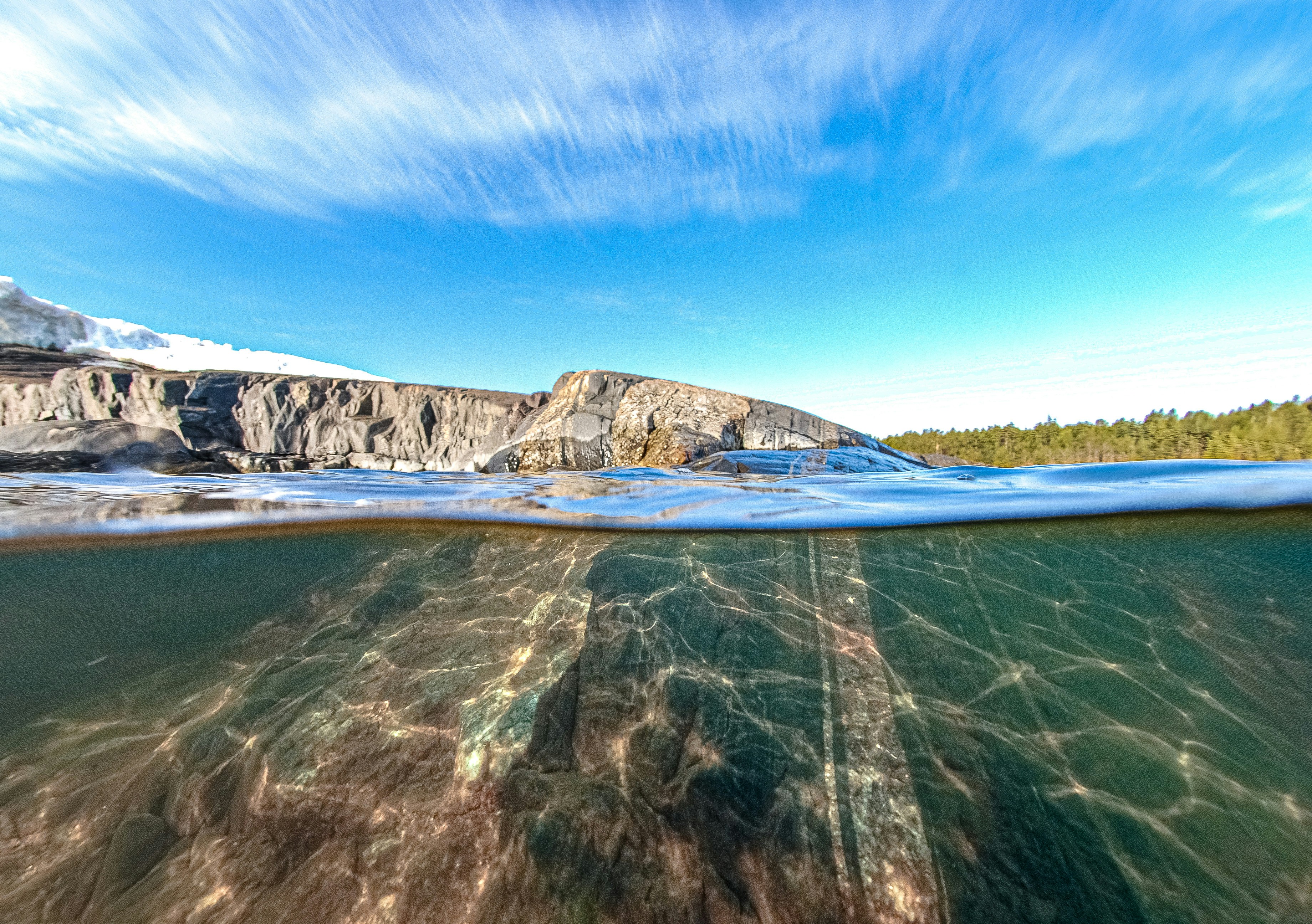 Split View: Rocky shoreline meeting crystal-green reef from a half-submerged vantage