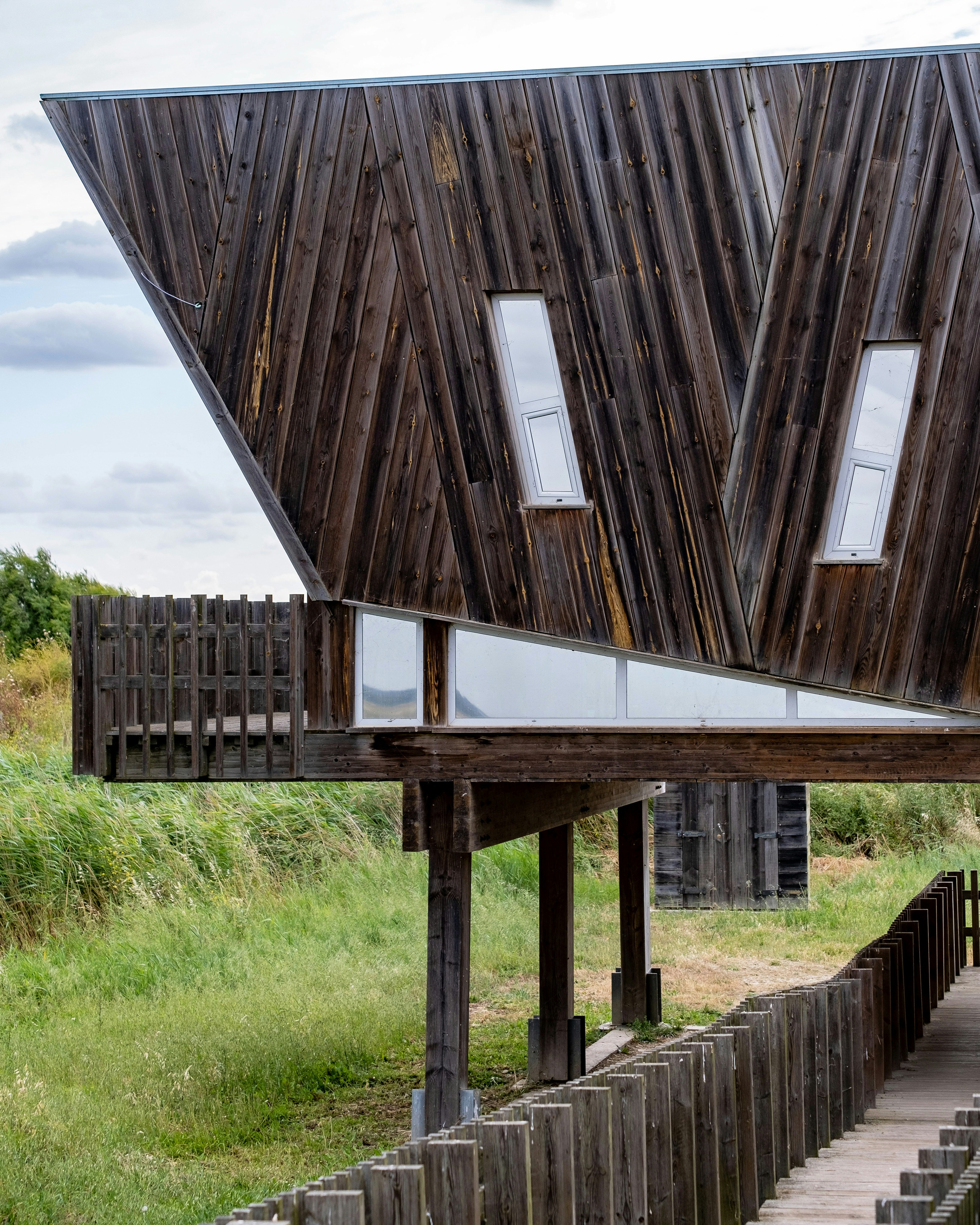Angled Timber House on Stilts Over a Field