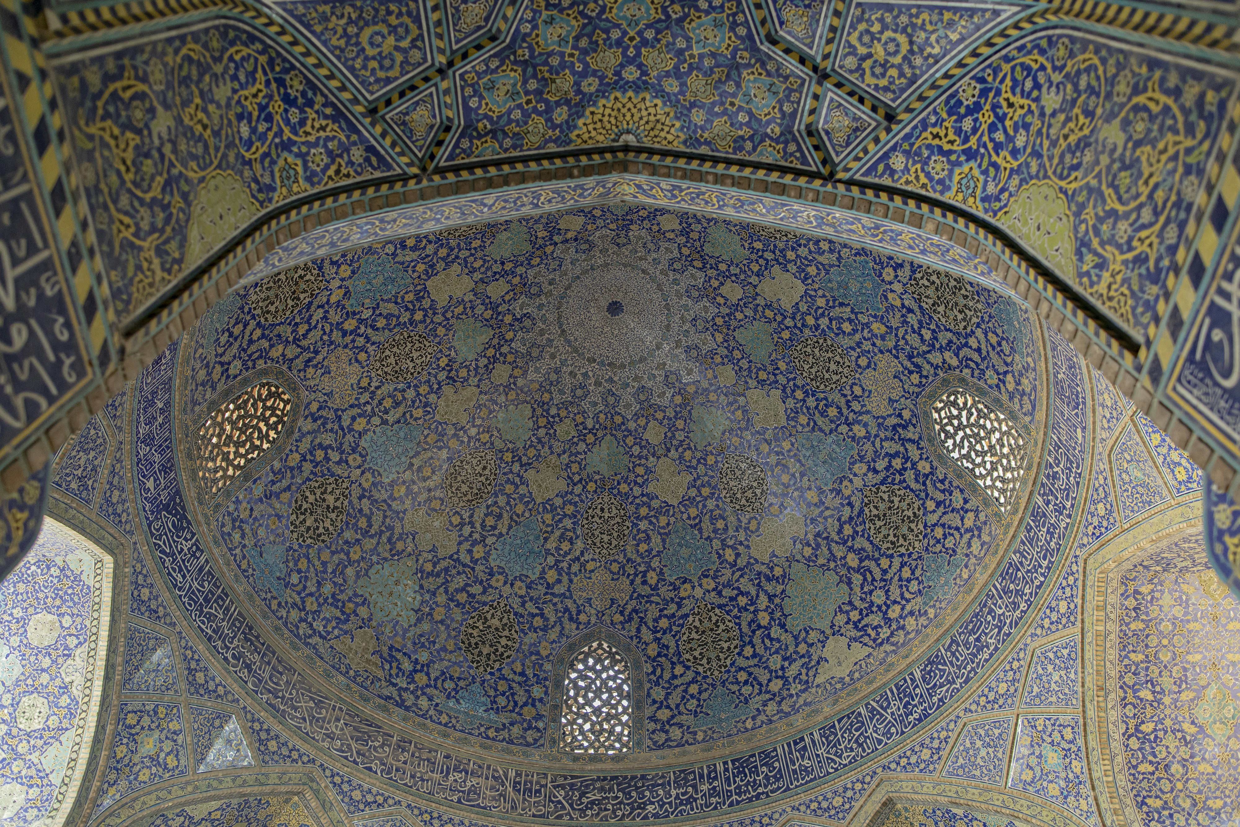 Intricate blue and gold patterns decorate the dome of a historic structure, showcasing exquisite craftsmanship and cultural artistry.