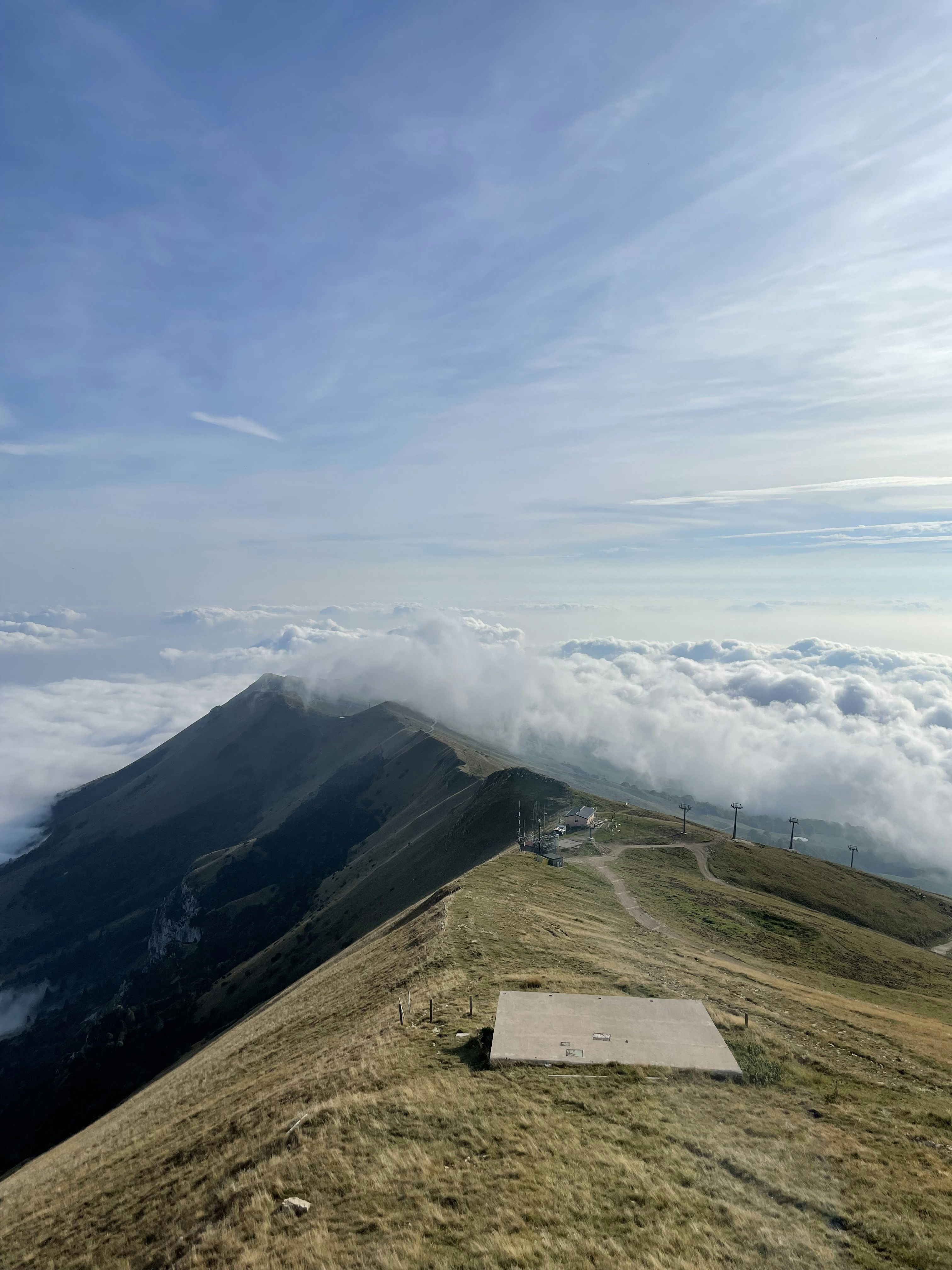 Edge of the World: Concrete Pad on a Knife-Edge Alpine Ridge Above the Clouds