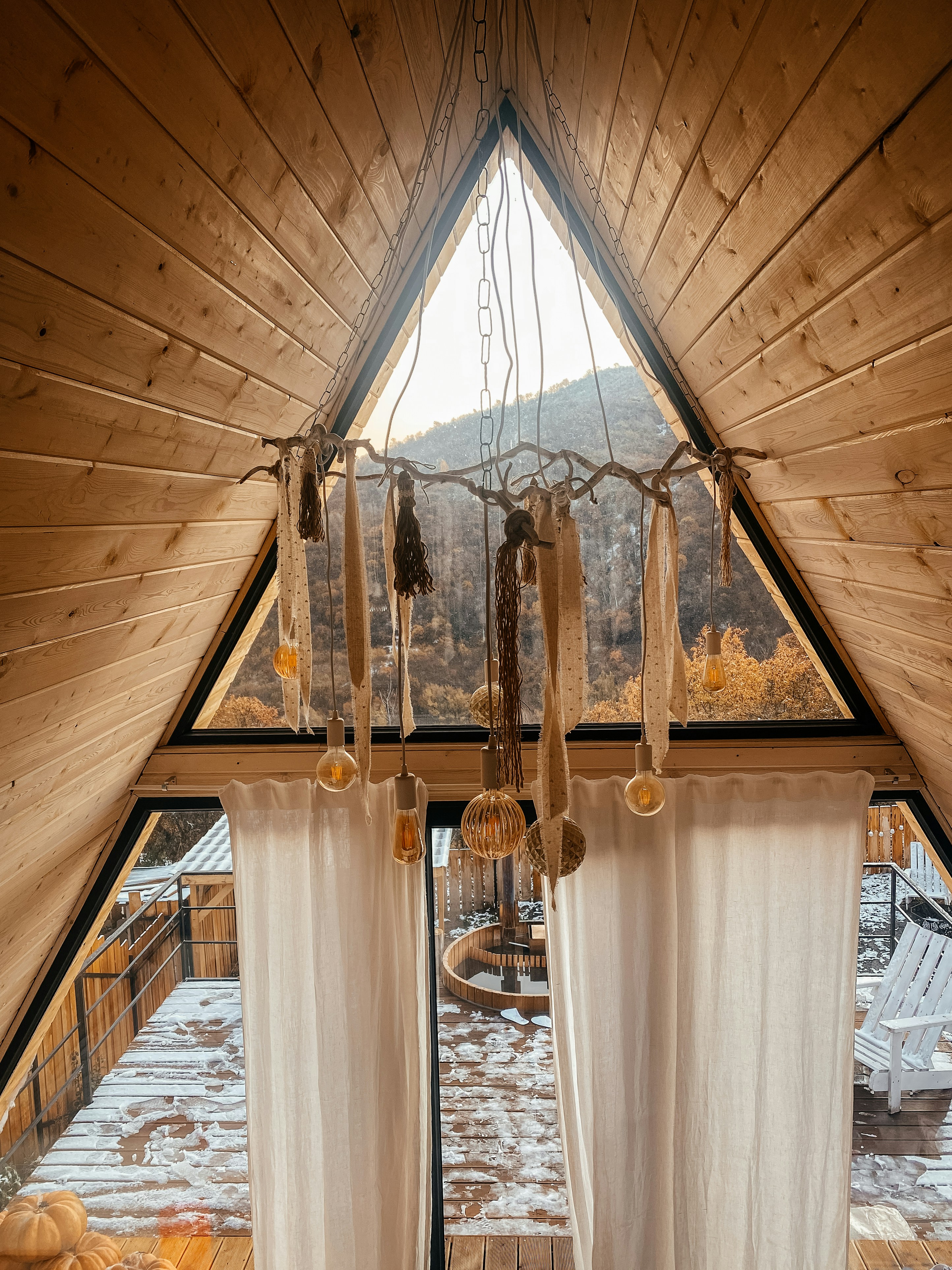 Triangle of Glow: A Cozy A-frame Interior Framing a Snowy Exterior Through a Curtain