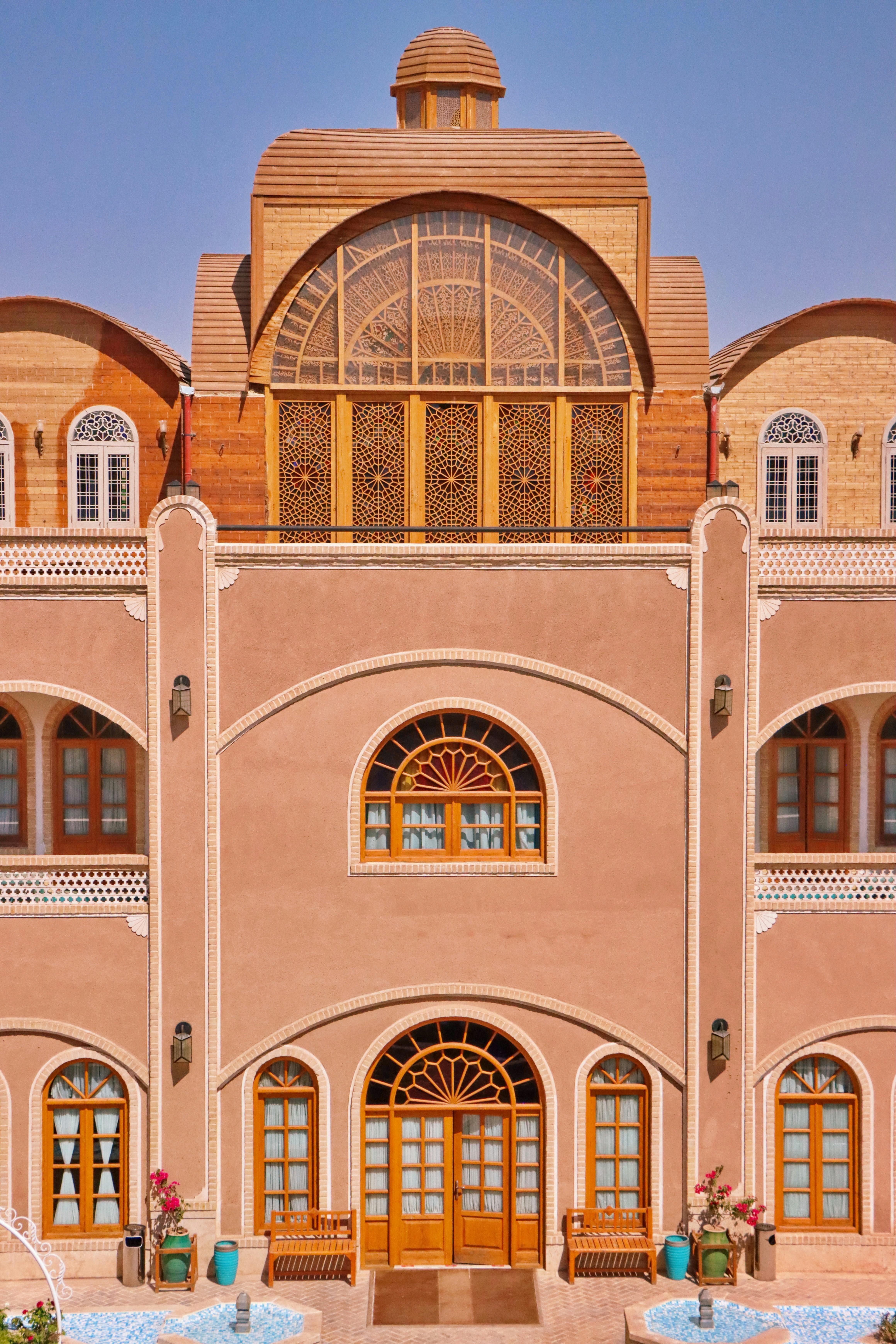 Intricate facade of a beautifully designed building showcasing traditional architecture with wooden accents and ornate windows. Floral arrangements enhance the inviting atmosphere.