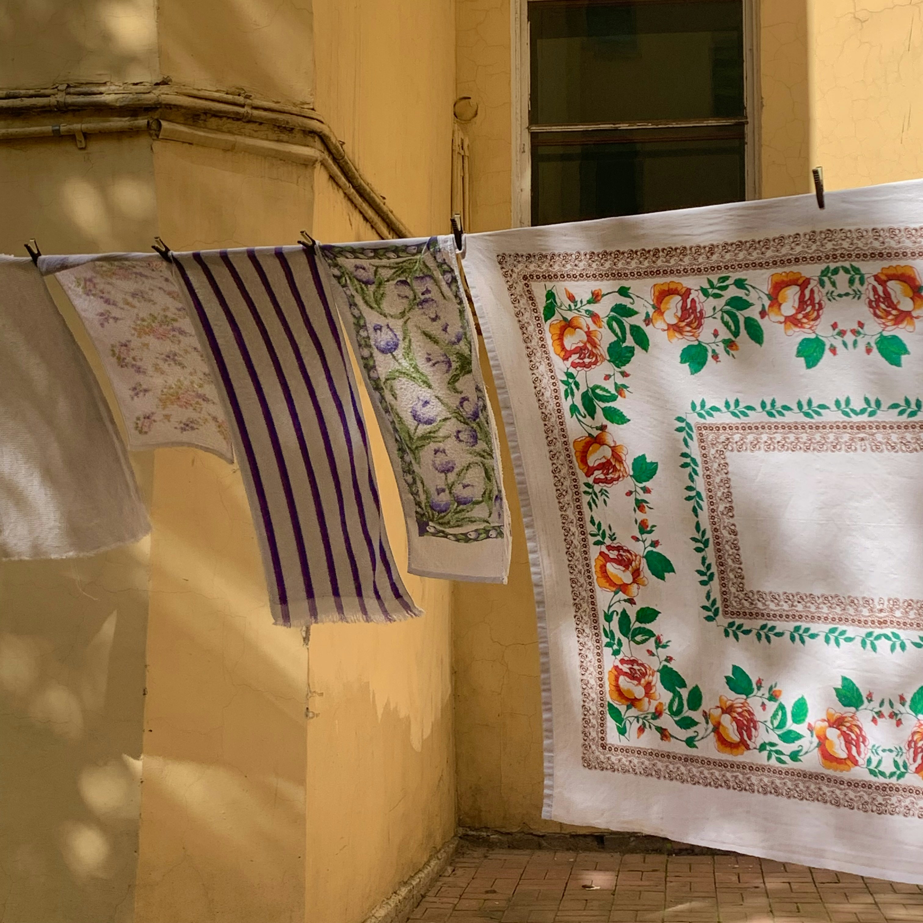 Sunlit Laundry Across a Yellow Courtyard Wall: Colorful Towels in Motion