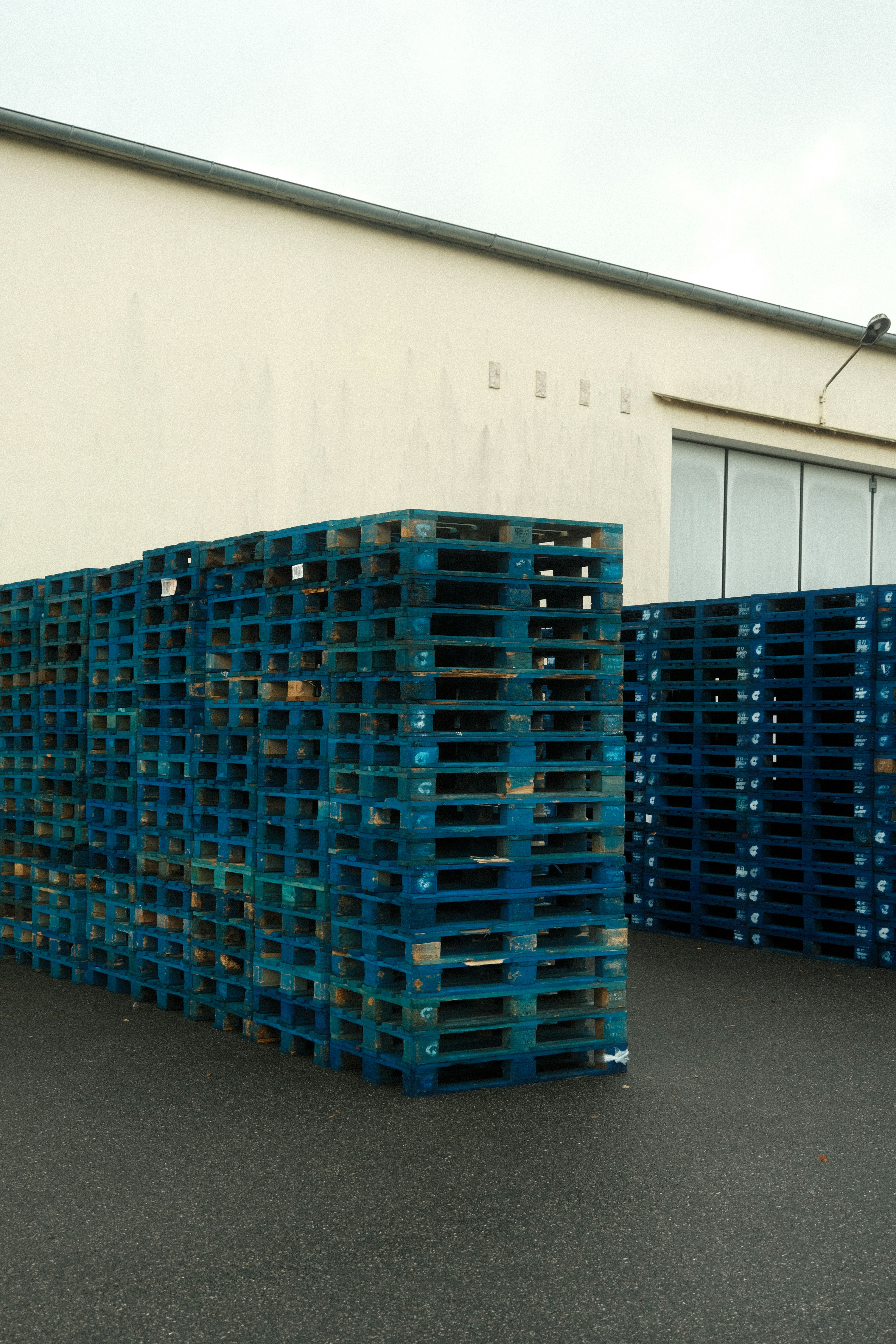 A large stack of blue pallets sitting in front of a building photo ...